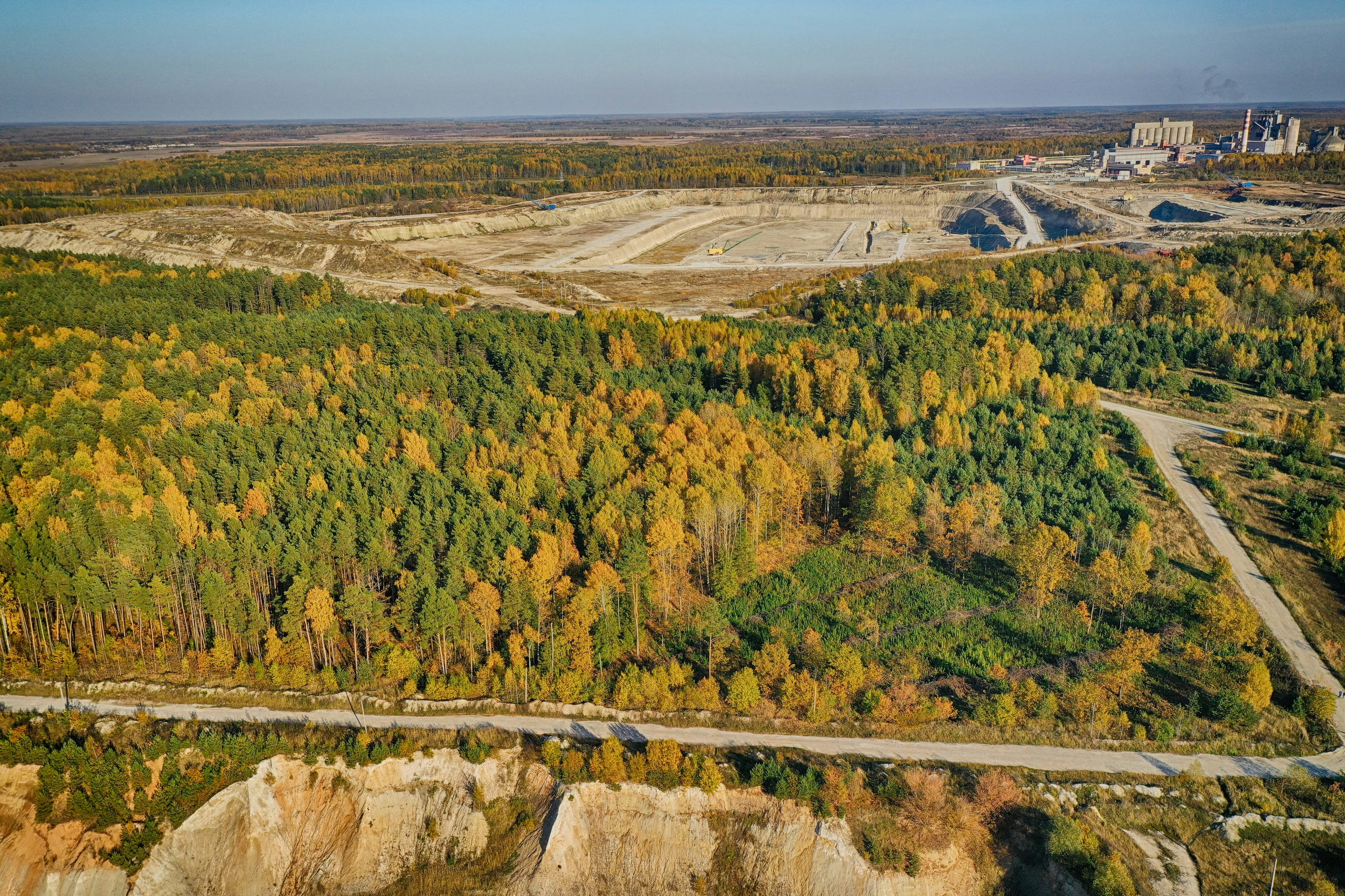 Autumn's Edge: Forest Crown Over a Distant Quarry