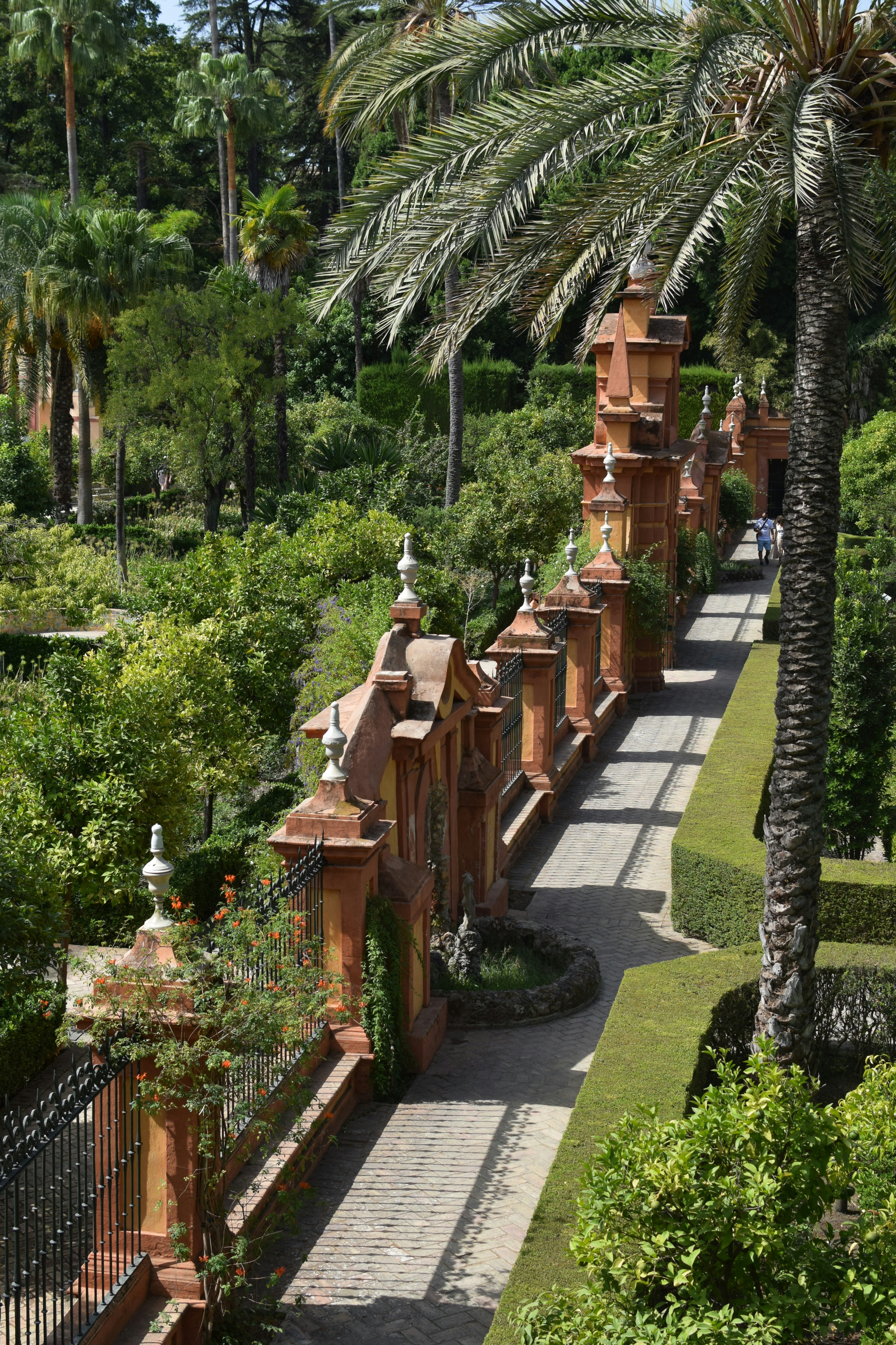 A serene garden pathway lined with ornate walls and vibrant greenery, inviting exploration and tranquility.