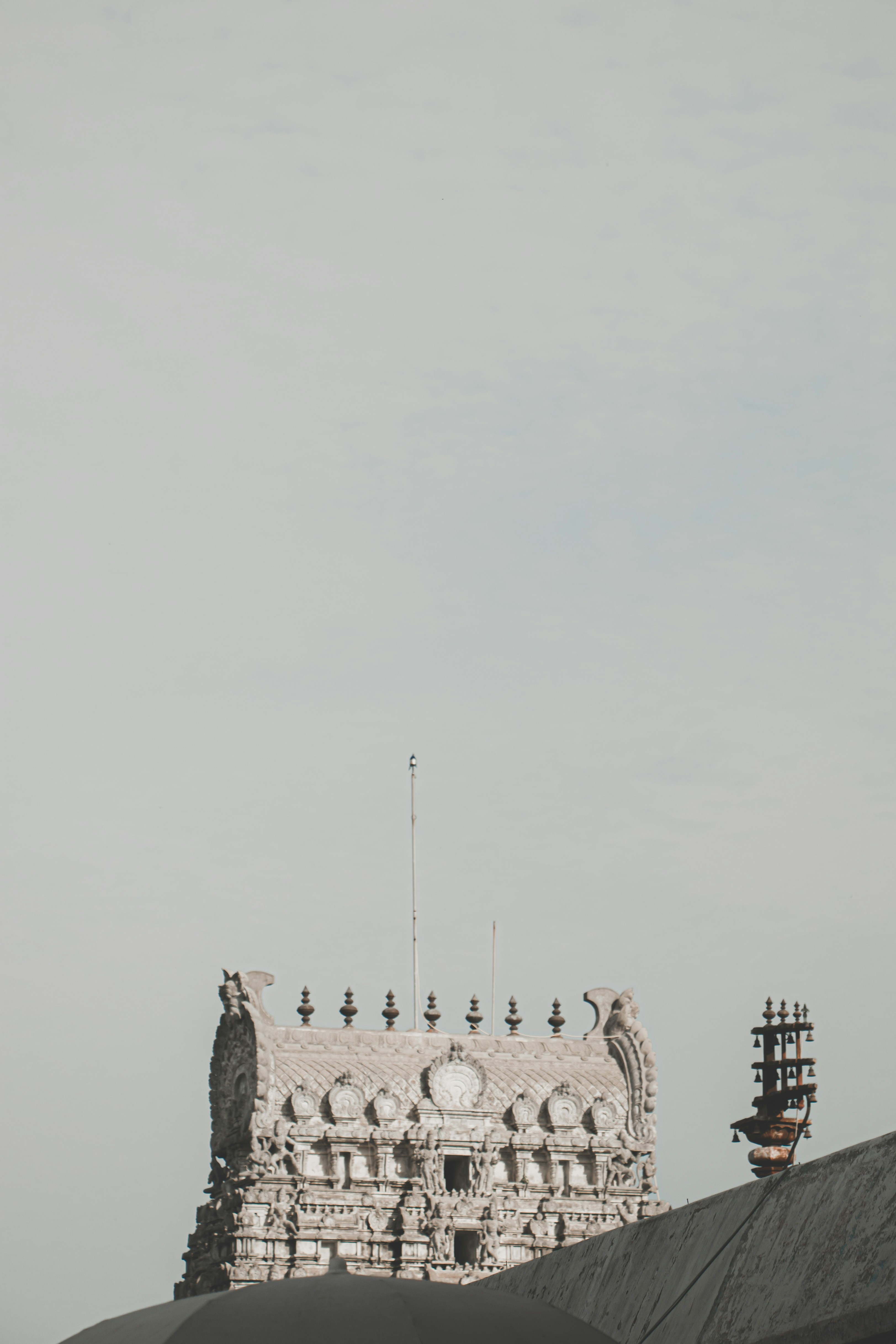 Gopuram Above the Roofline: An Ornate South Indian Temple Tower Against a Pale Sky