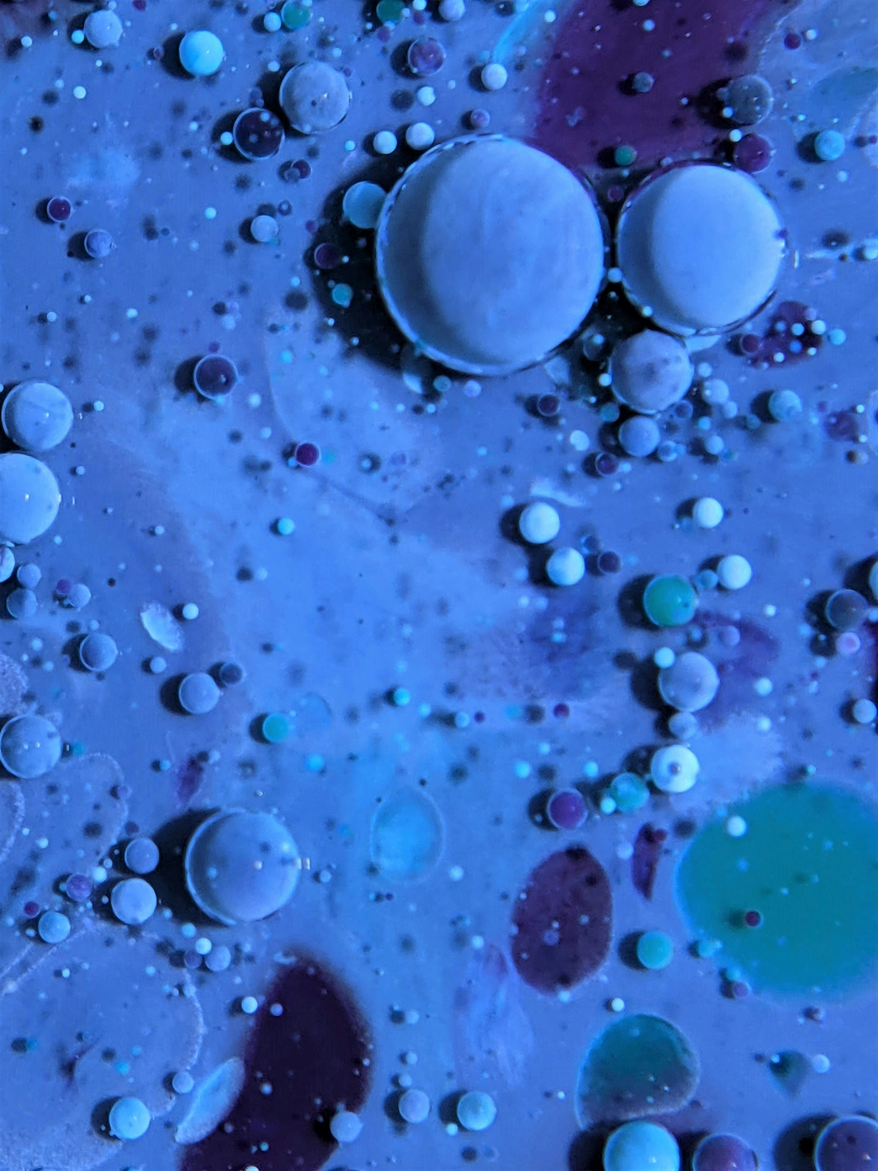 Abstract composition of vibrant circular shapes and speckles in a fluid medium, showcasing a mesmerizing blend of colors and textures.