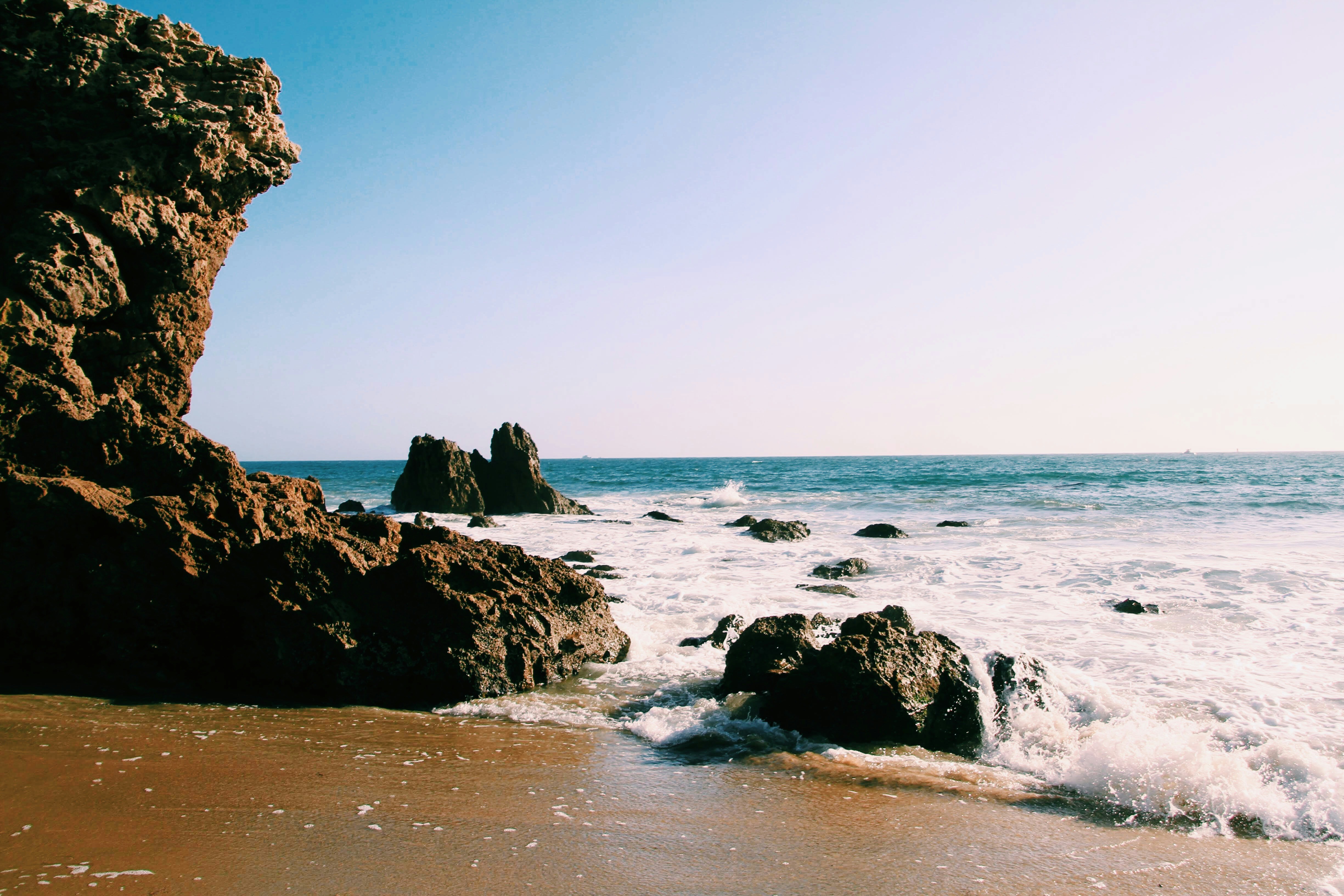 Foto zum Thema Ein felsiger Strand mit Wellen, die ins und aus dem ...