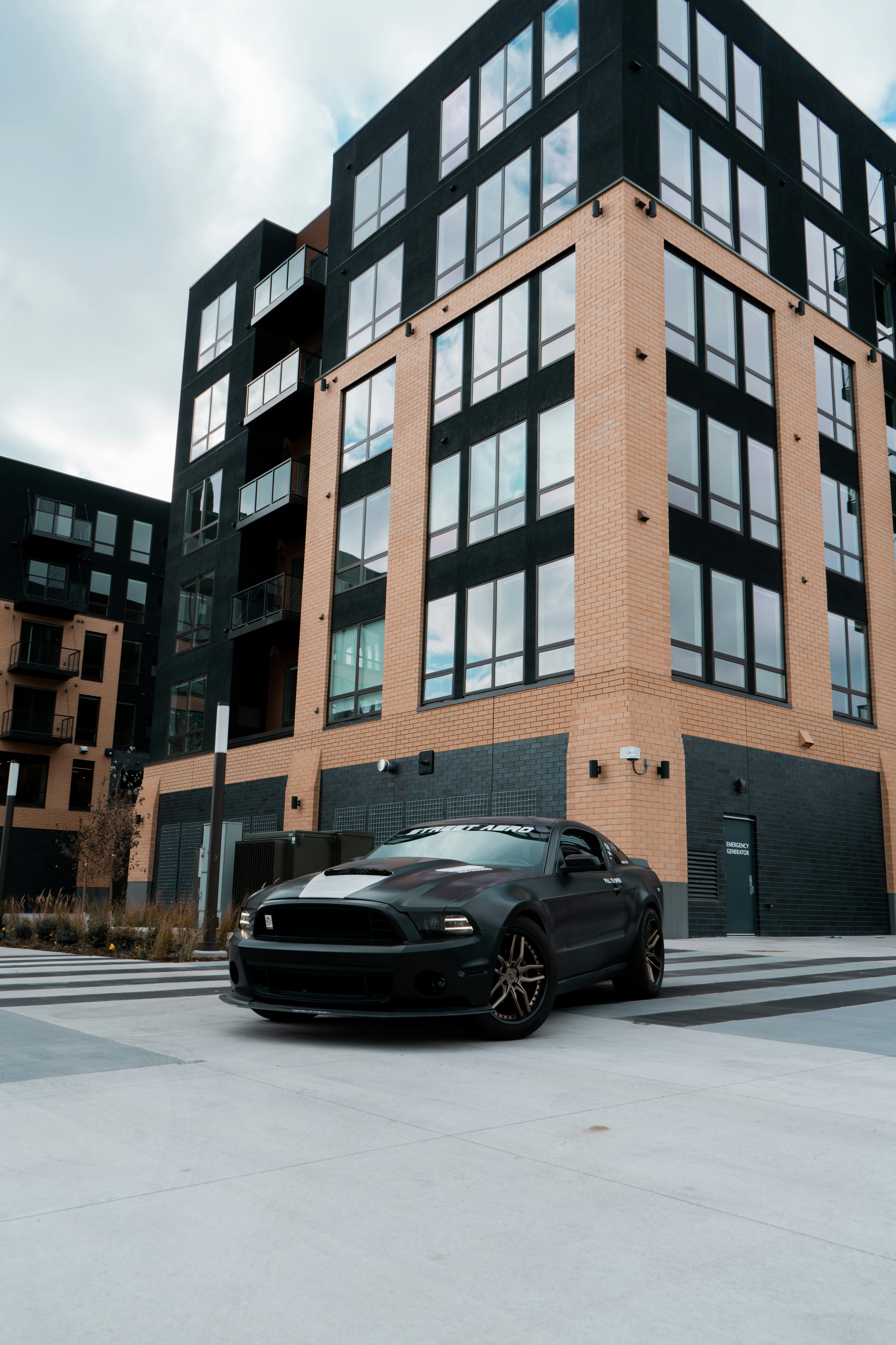 Black Mustang at the Threshold of a Brick-and-Glass Urban Block
