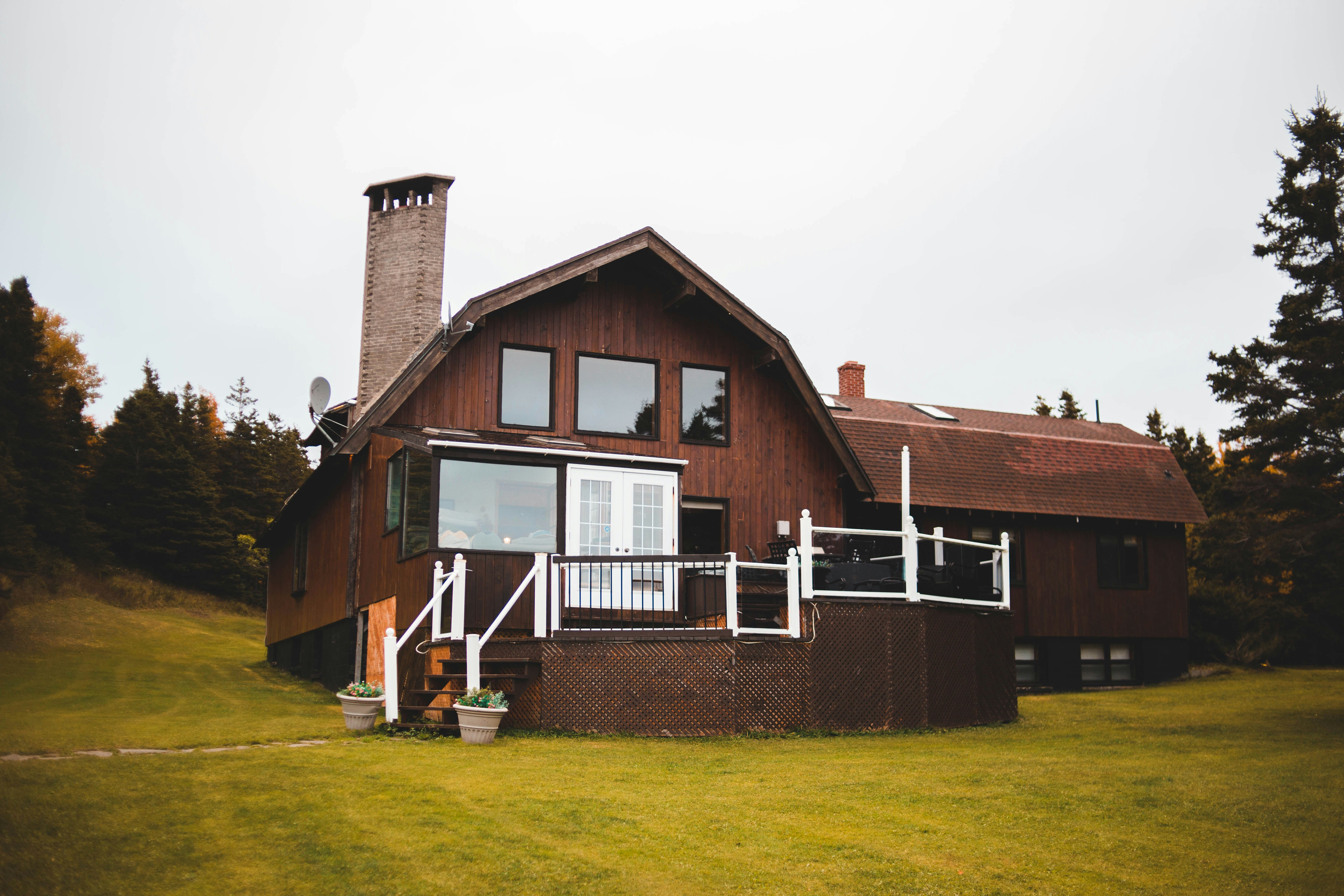 Foto Una casa marrón con barandillas blancas y una chimenea – Imagen ...