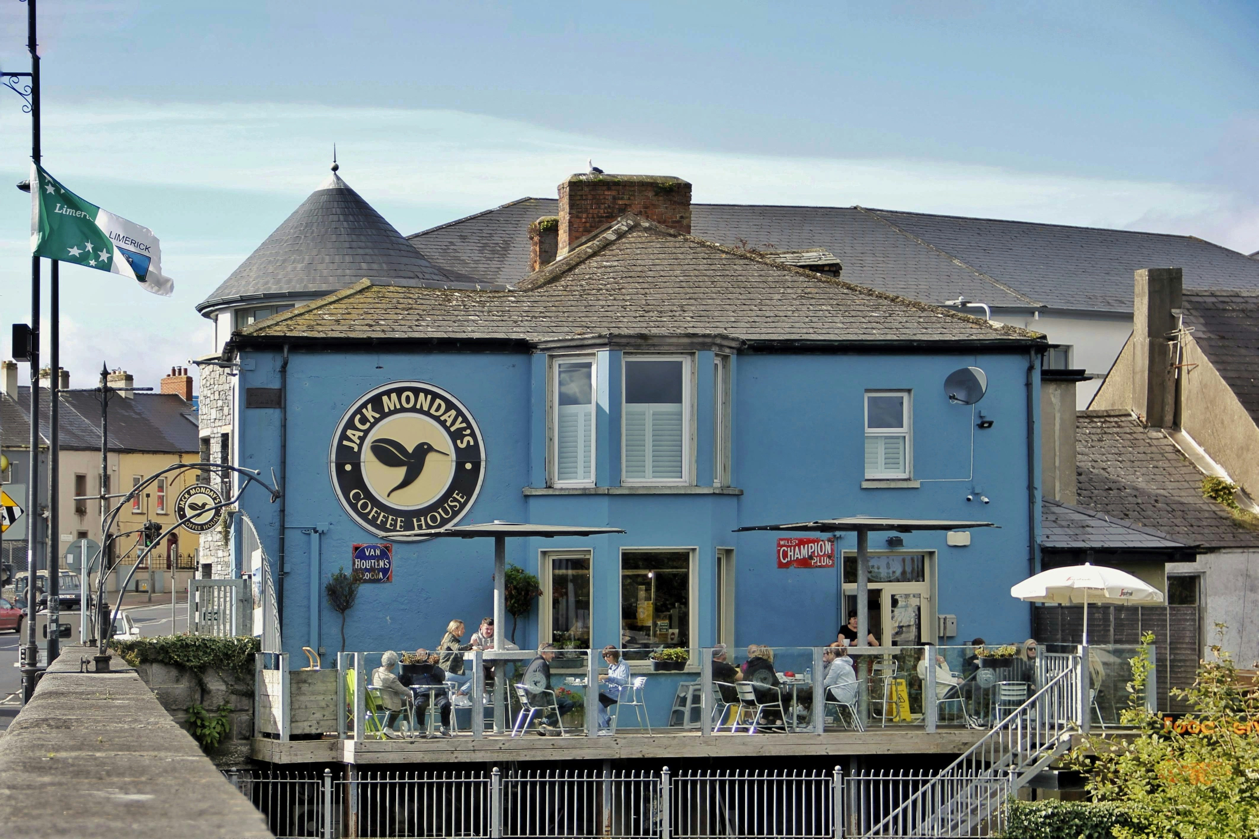 Charming blue coffee house with outdoor seating, nestled by the waterfront, inviting patrons to enjoy a relaxing atmosphere.