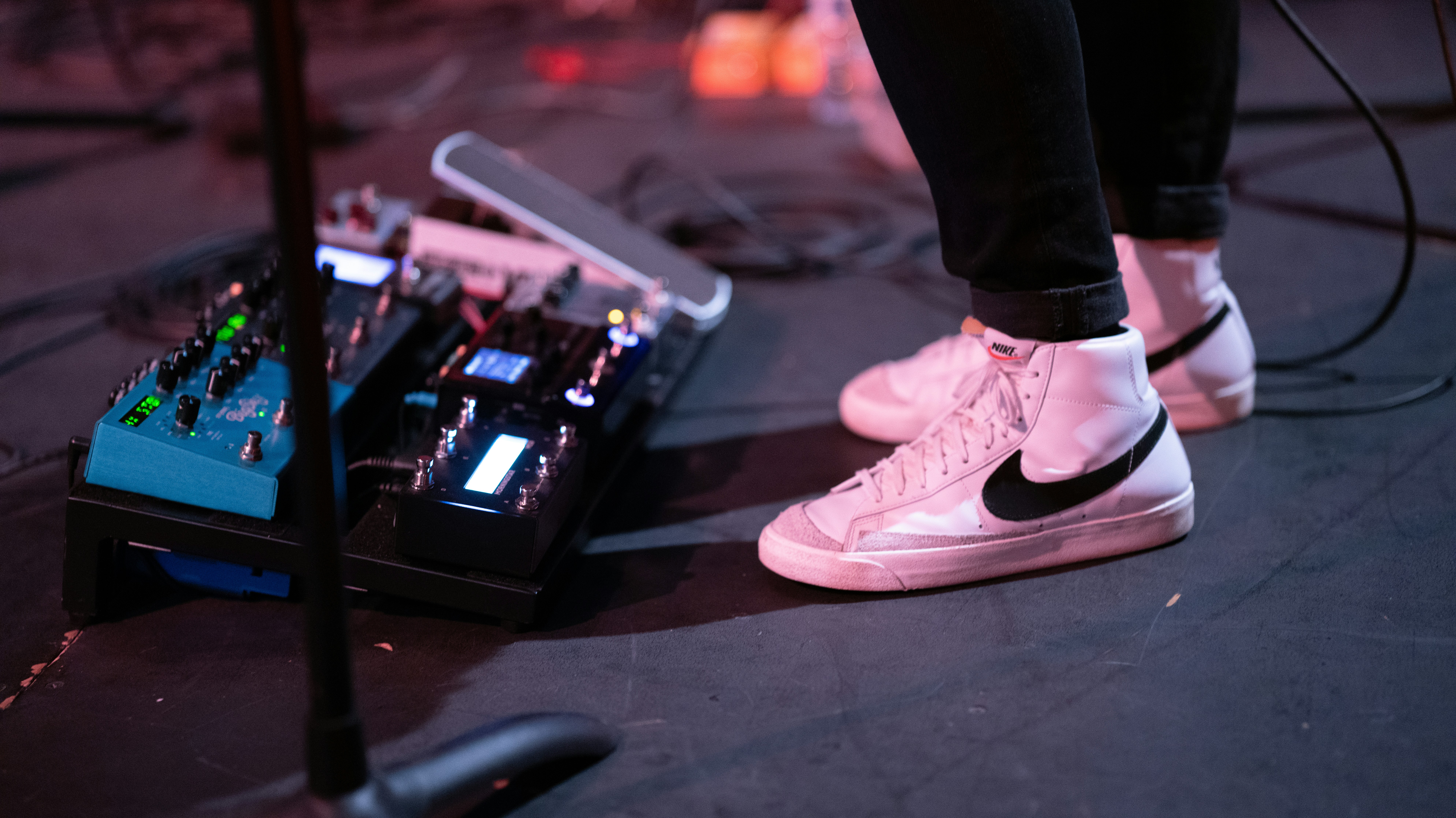 Close-up of a musician's foot on a guitar pedalboard, showcasing the interaction between footwear and equipment during a live performance.