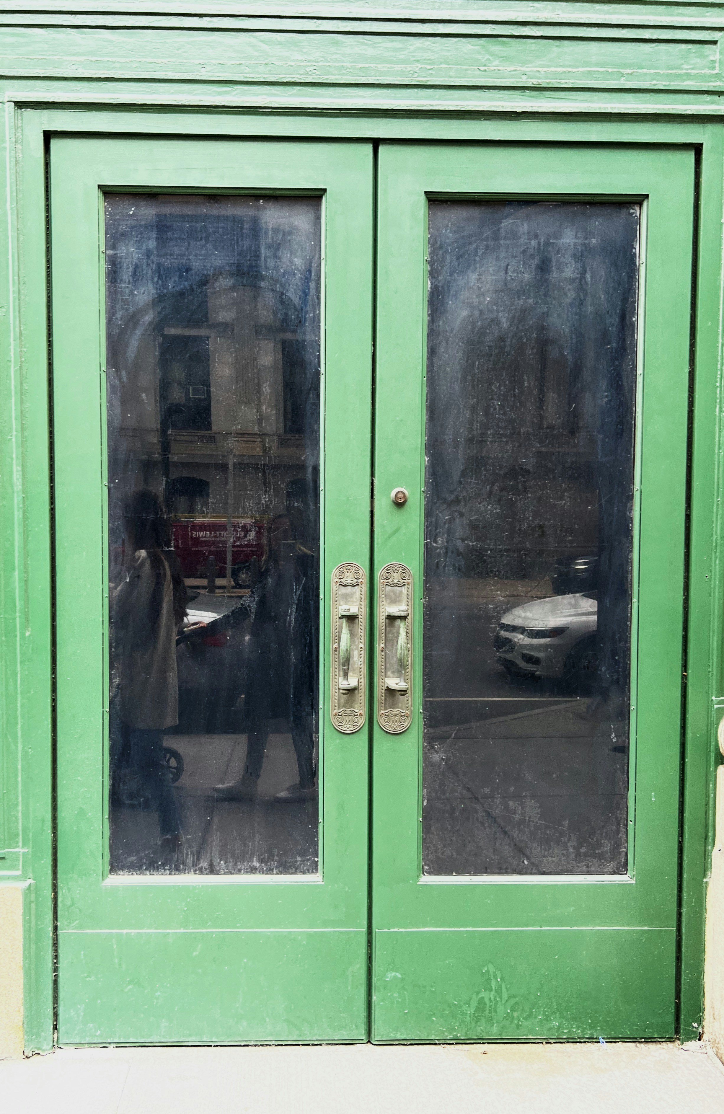 a man walking past a green door on a sidewalk