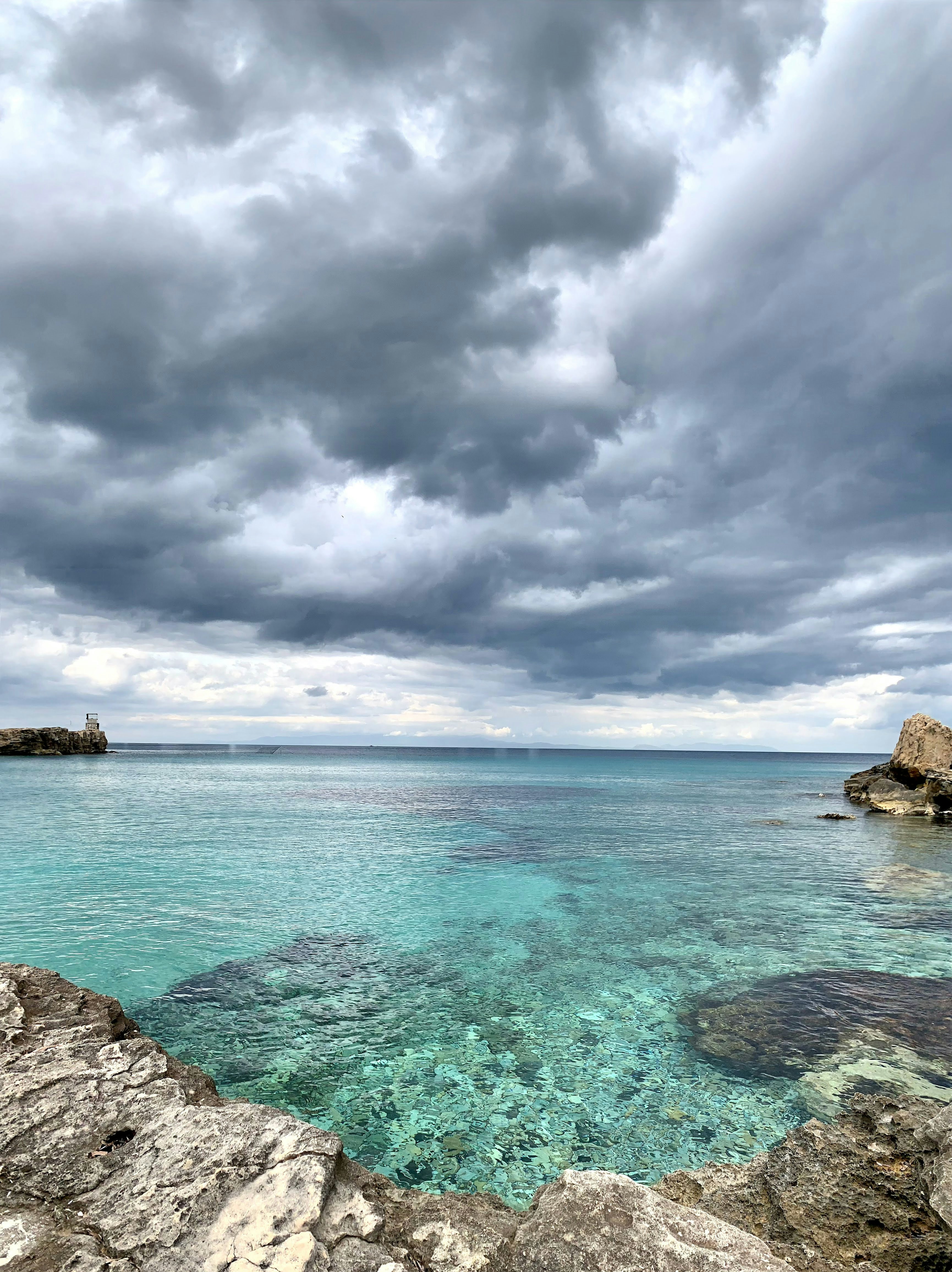 Stormy horizon over crystal cove with rugged foreground rocks