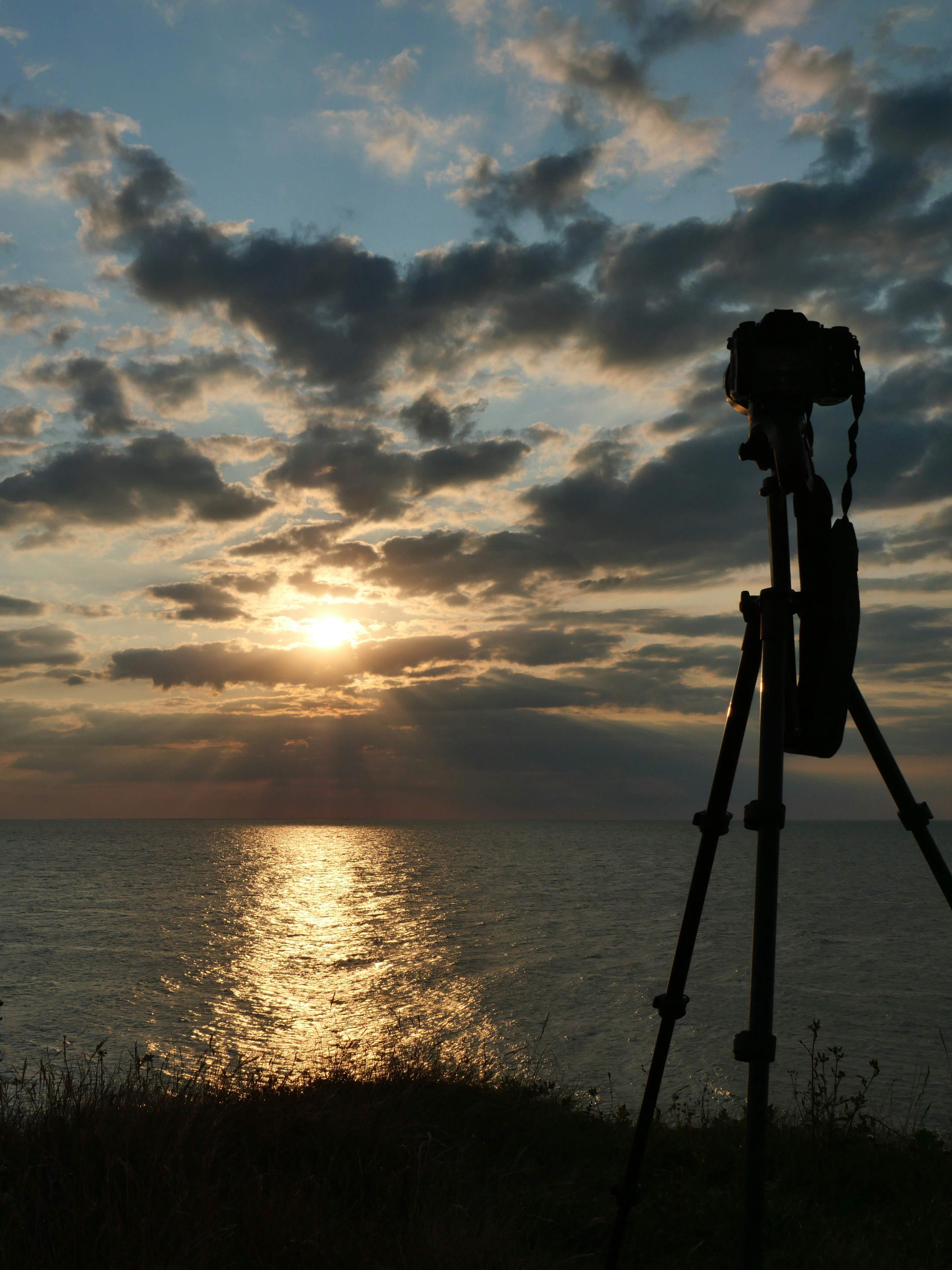 Sunset Sentinel: Tripod Silhouette Against a Quiet Sea Horizon