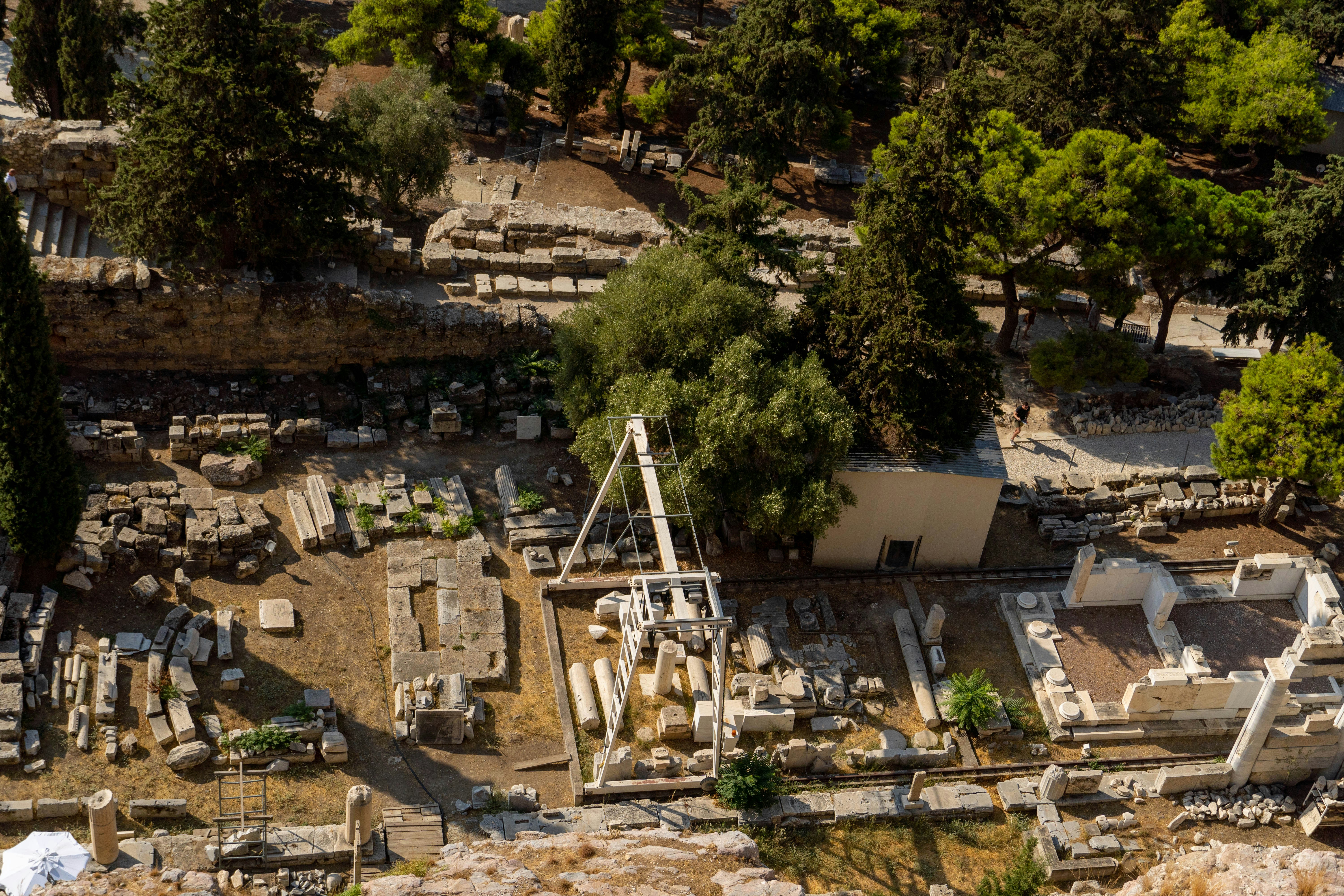 Crane Over Ancient Quarry: Aerial Worksite Among Stones and Pines