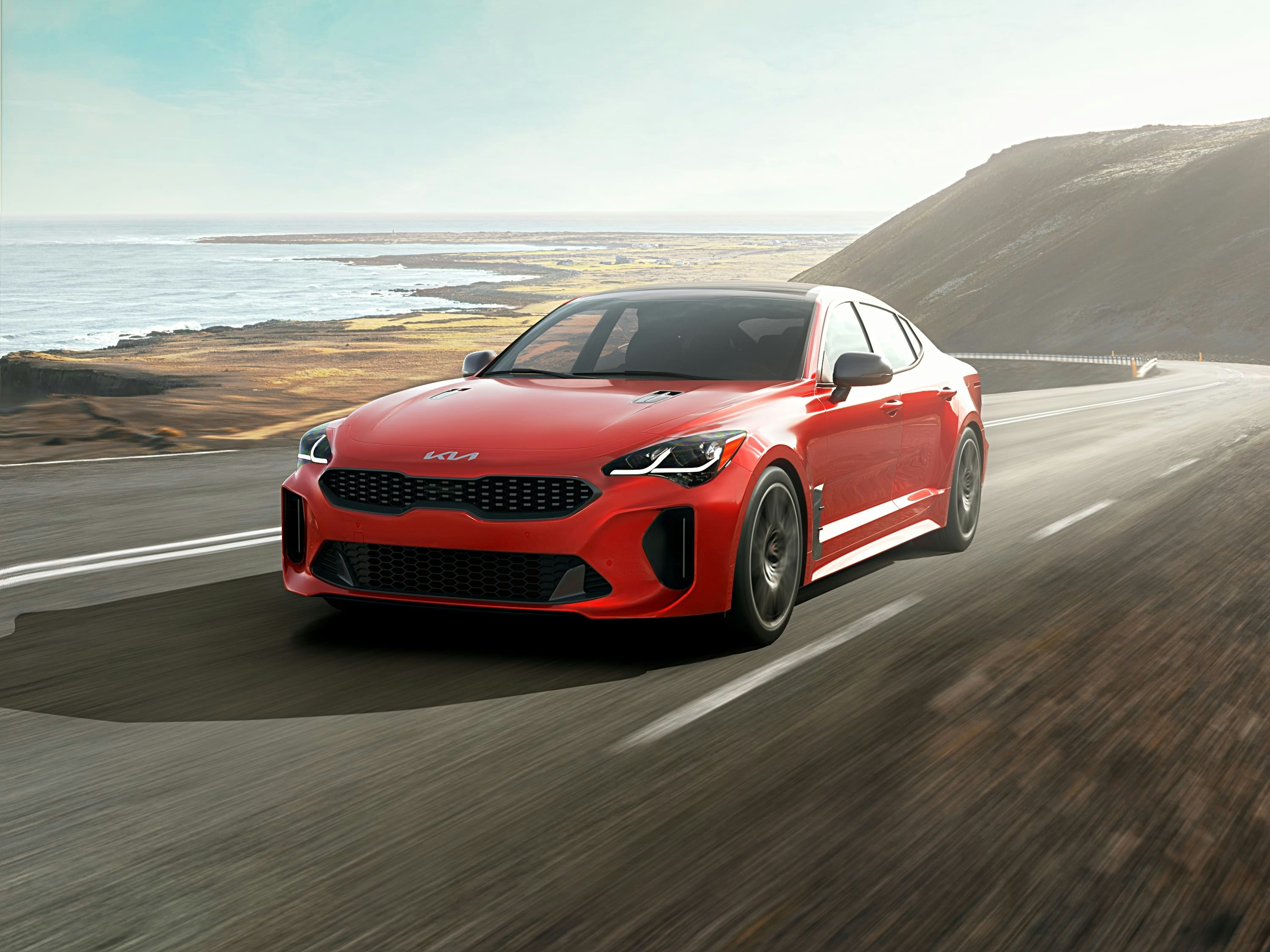 A red car driving down a road next to the ocean photo – Free Digital ...
