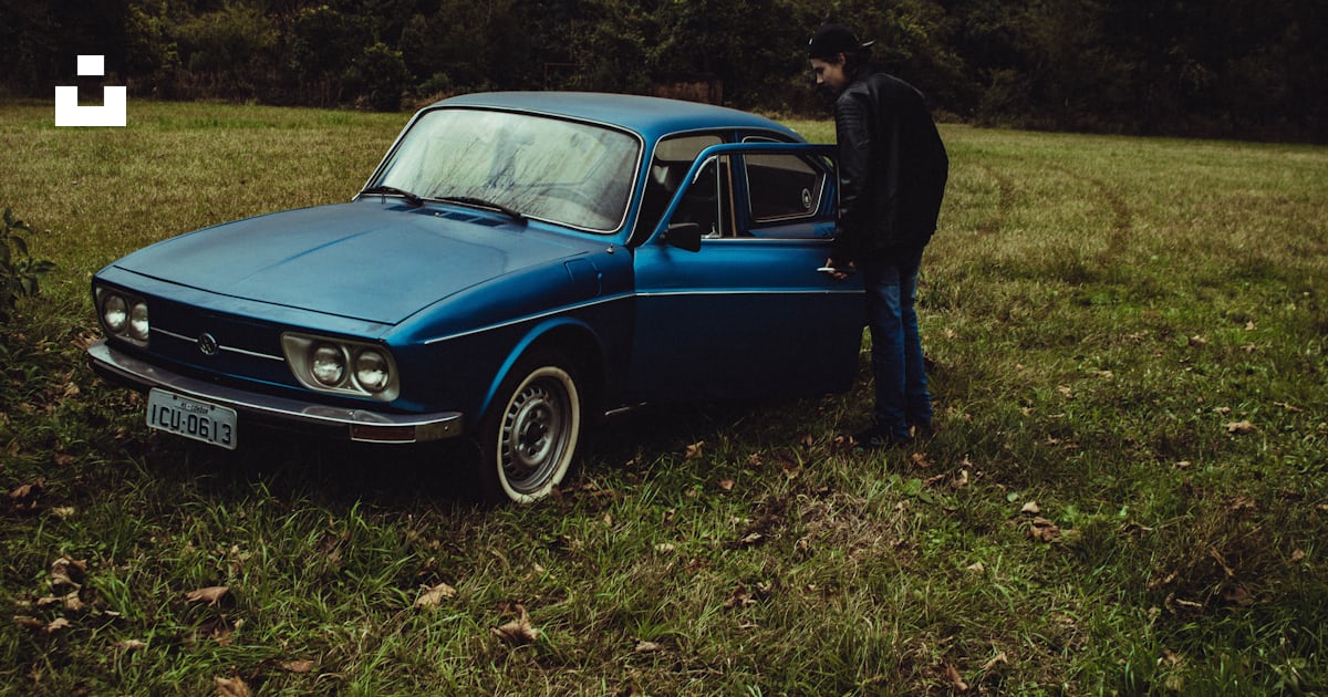 Un Homme Debout à Côté Dune Voiture Bleue Dans Un Champ Photo Photo
