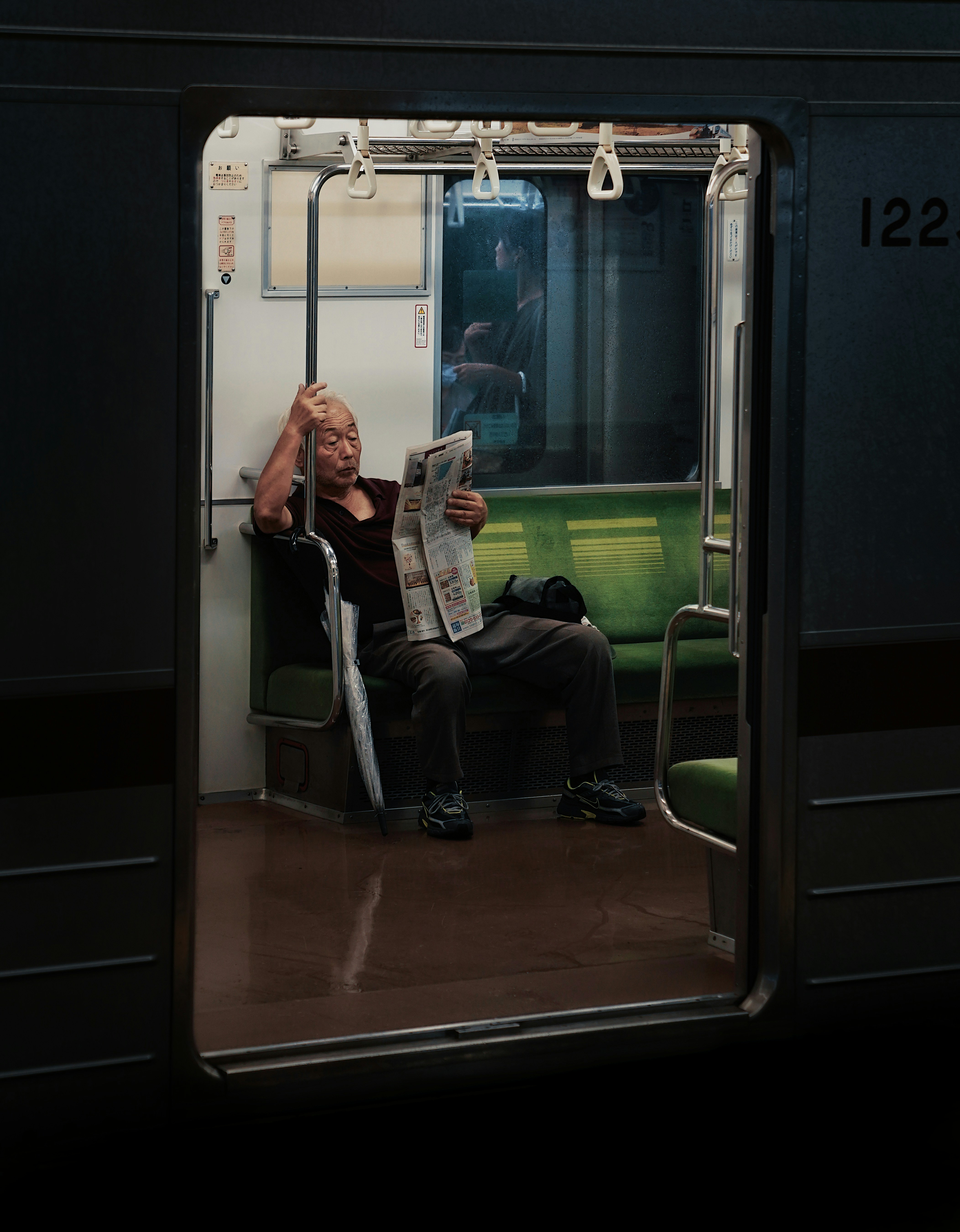 An elderly man reading a newspaper in a nearly empty subway car, highlighting moments of solitude in urban life.
