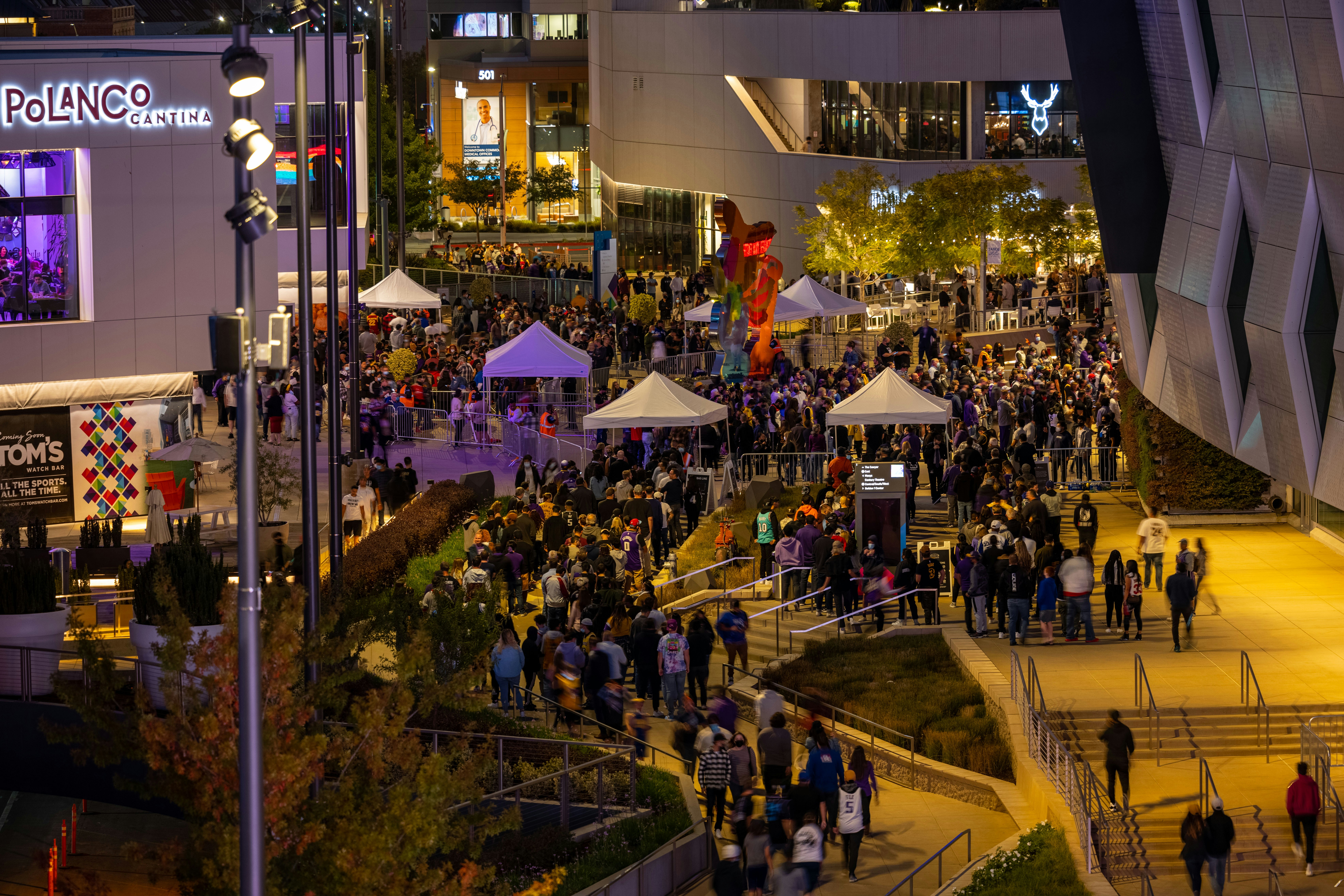 A crowd of people walking down a street next to tall buildings photo ...