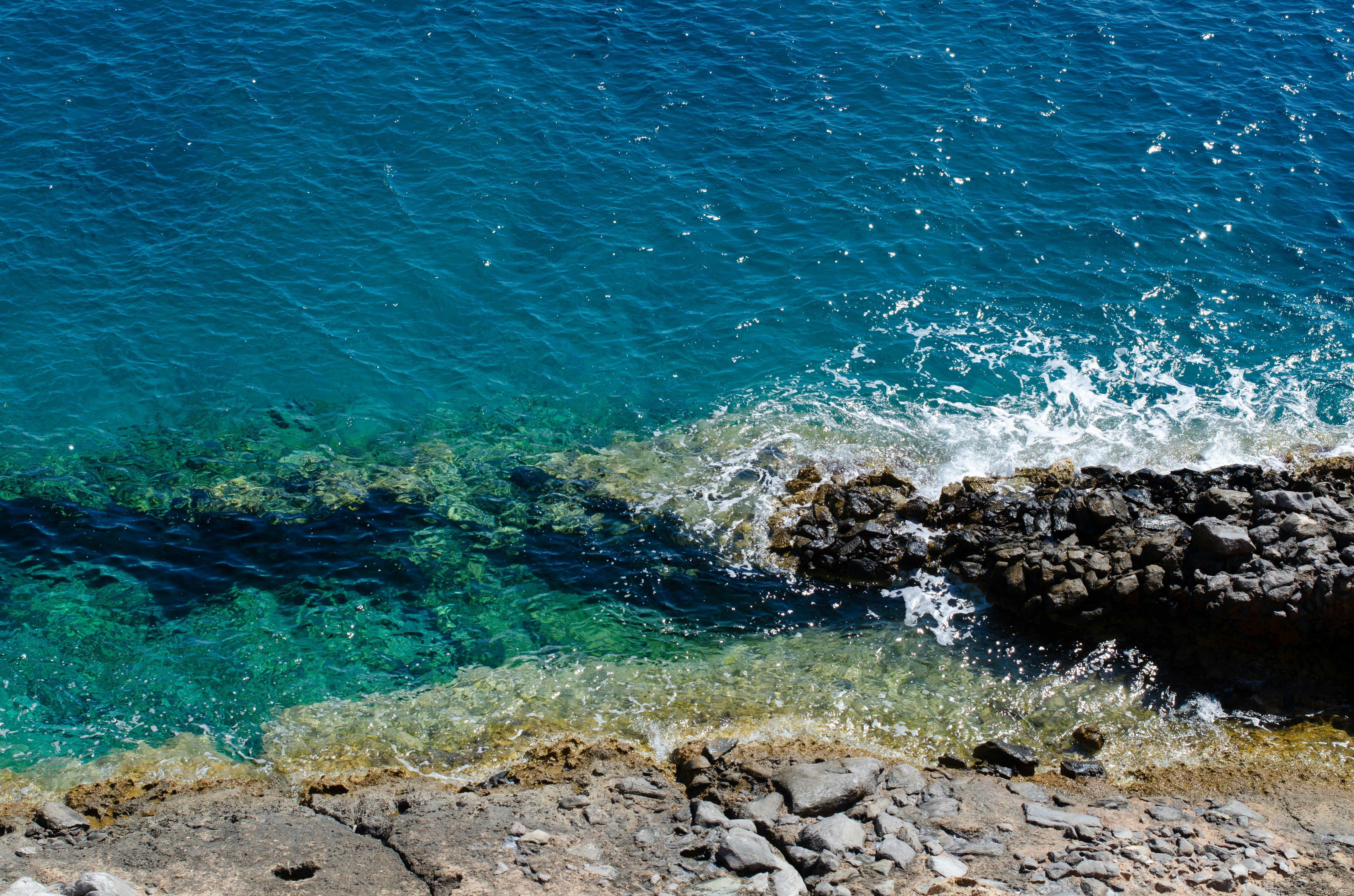 A body of water surrounded by rocks and water photo – Free Sea Image on ...
