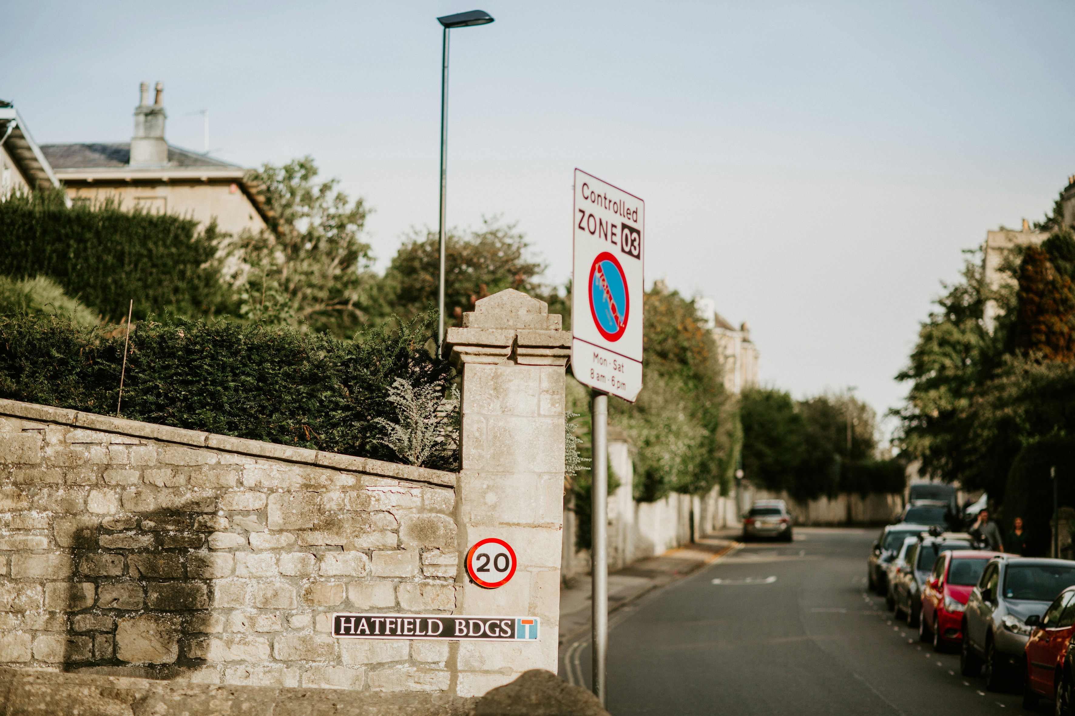 Street view featuring a speed limit sign and parking restriction notice alongside a quiet residential road. The setting reflects a calm urban environment.