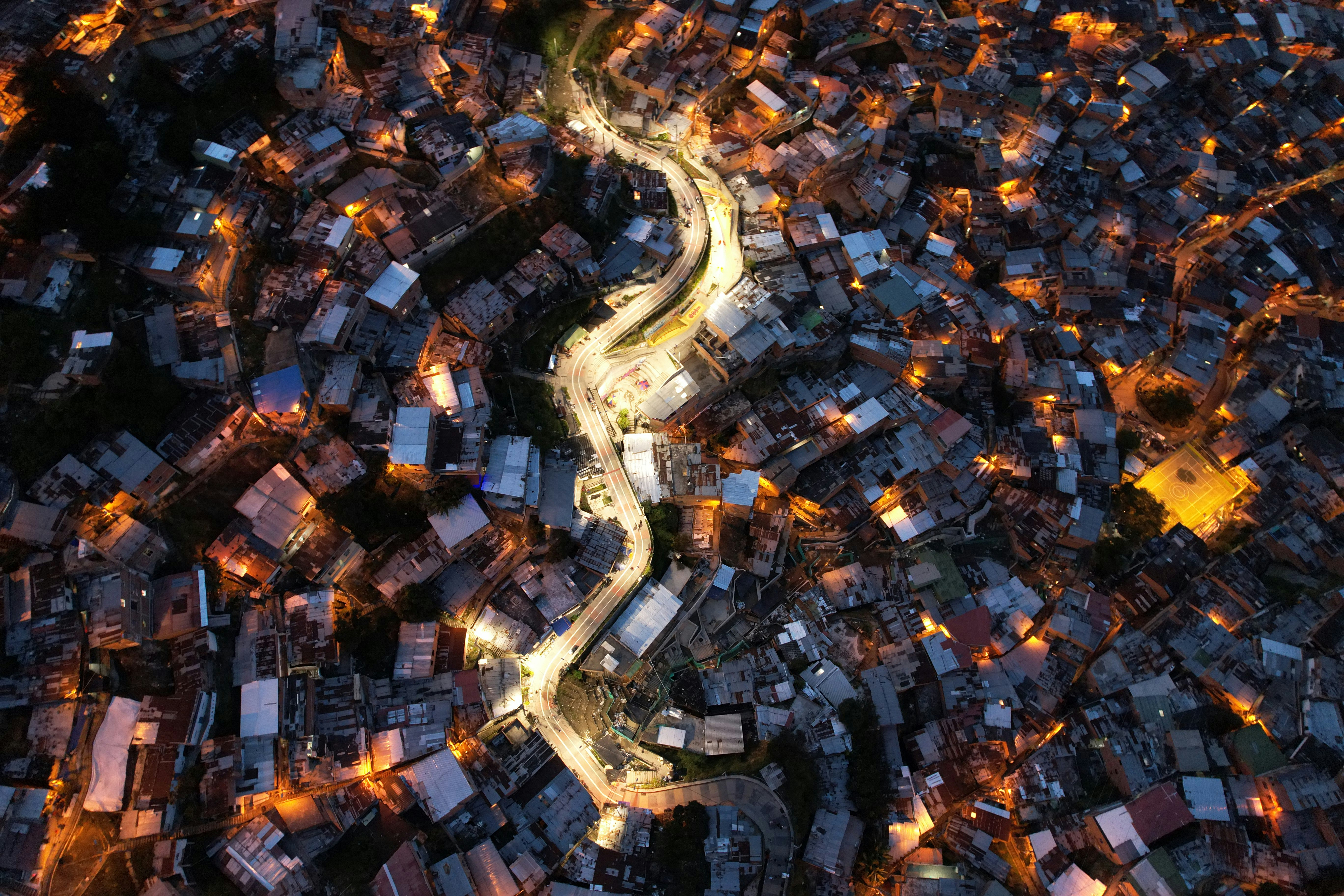Aerial view of a winding street illuminated in a densely packed urban area at night.
