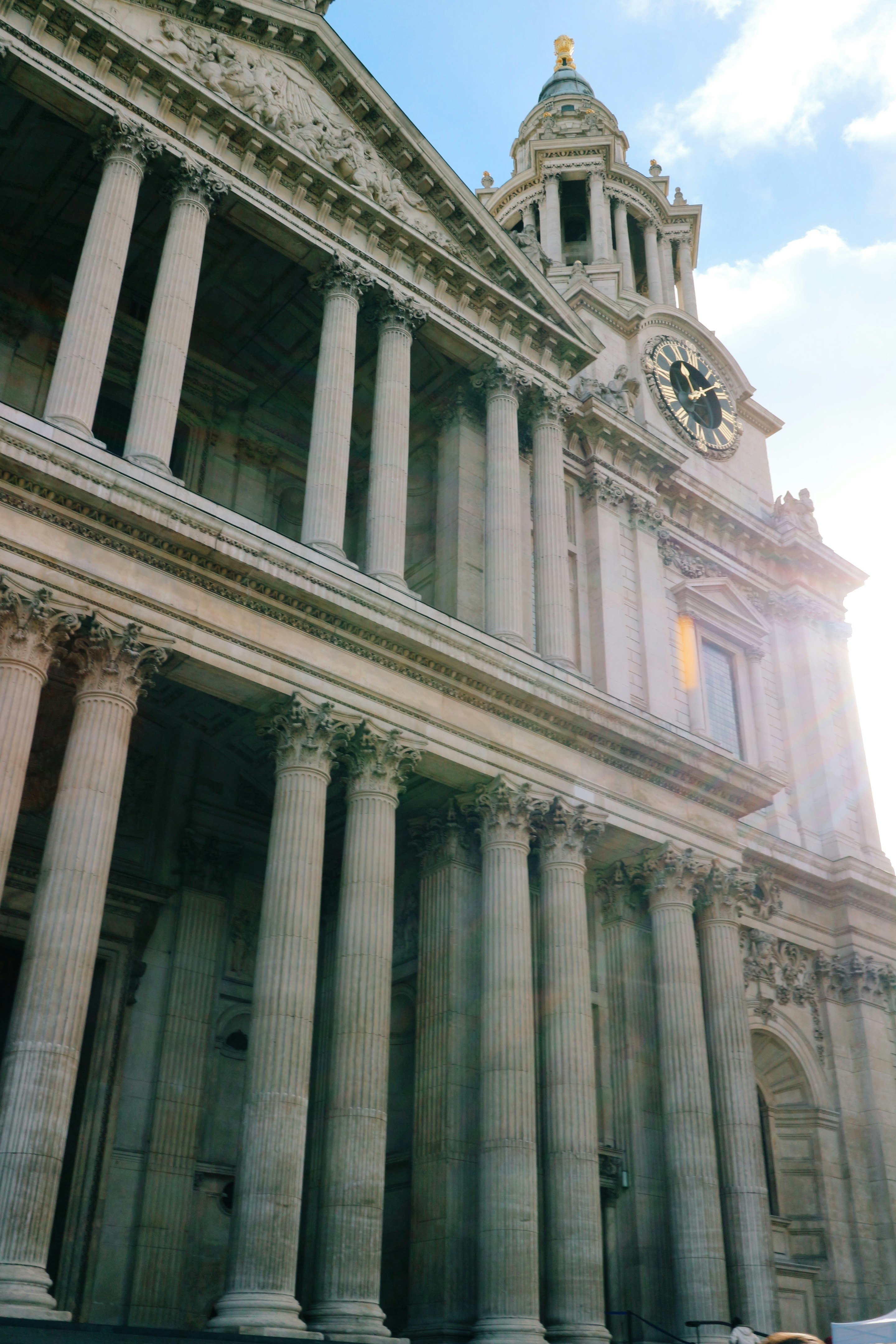 Morning Light Over a Neoclassical Facade: Columns, Clock, and Sunflare