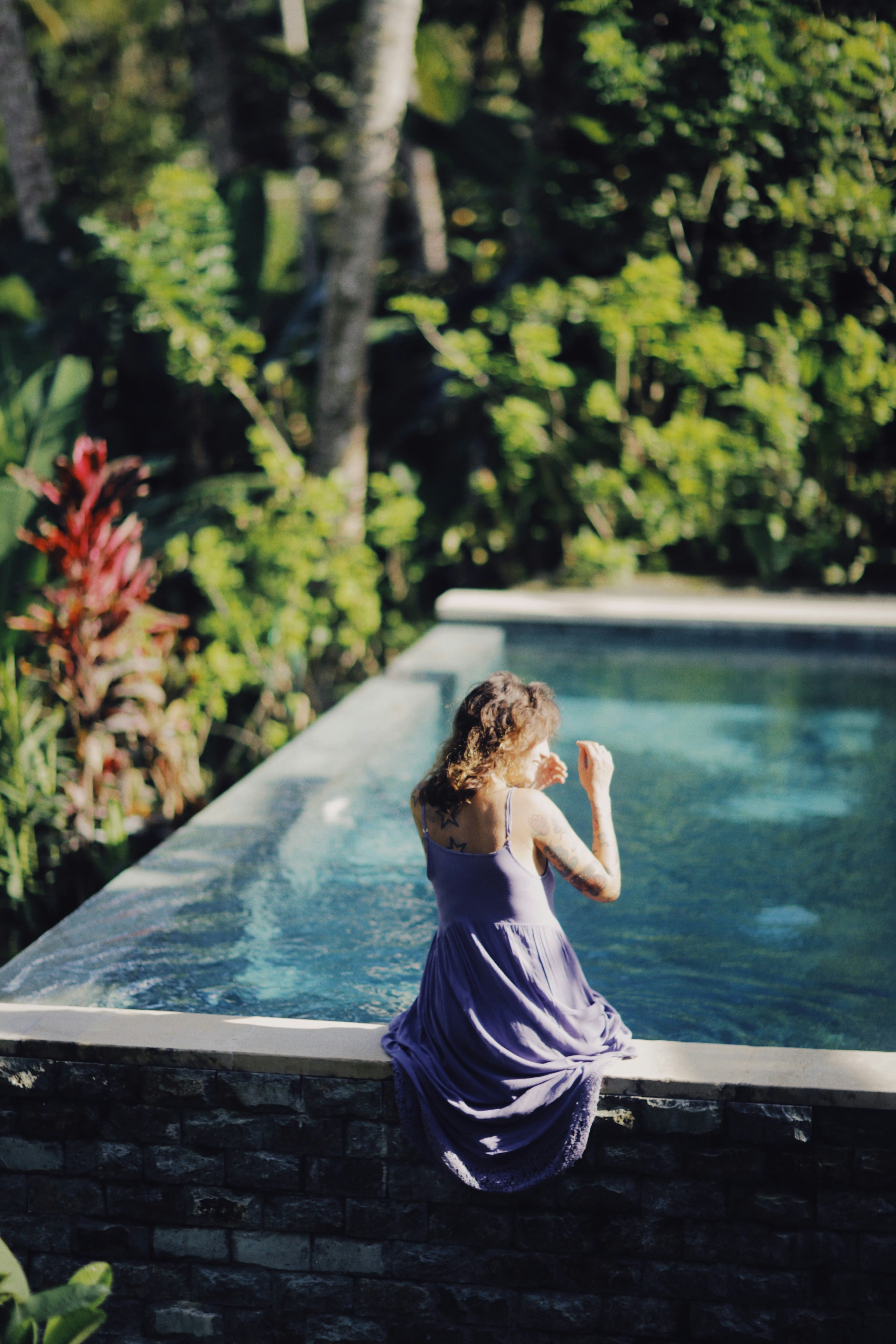 A woman in a purple dress sitting by a pool photo – Free Clothing Image ...