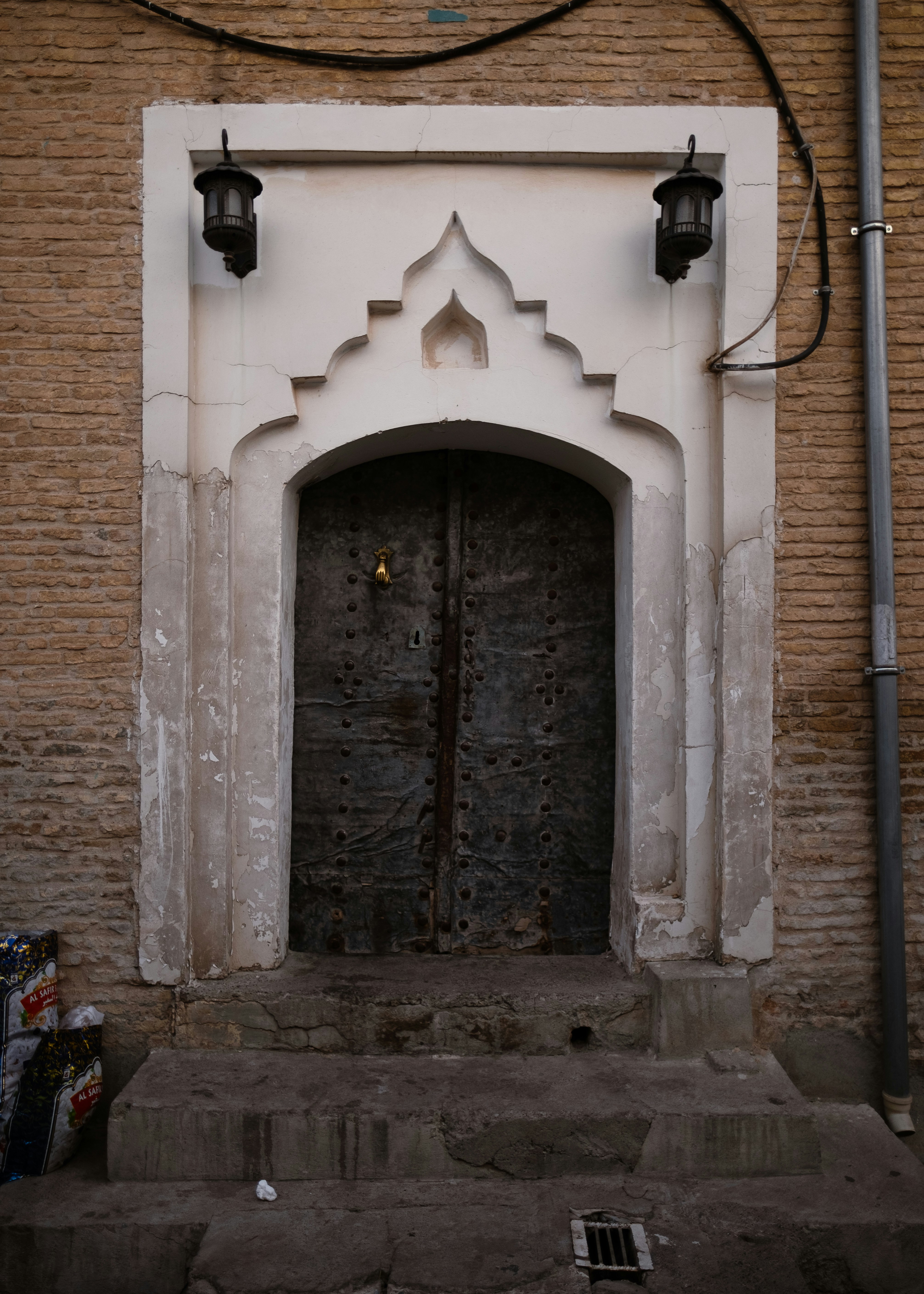 Intricately designed wooden door framed by weathered walls and vintage lanterns, showcasing architectural heritage.