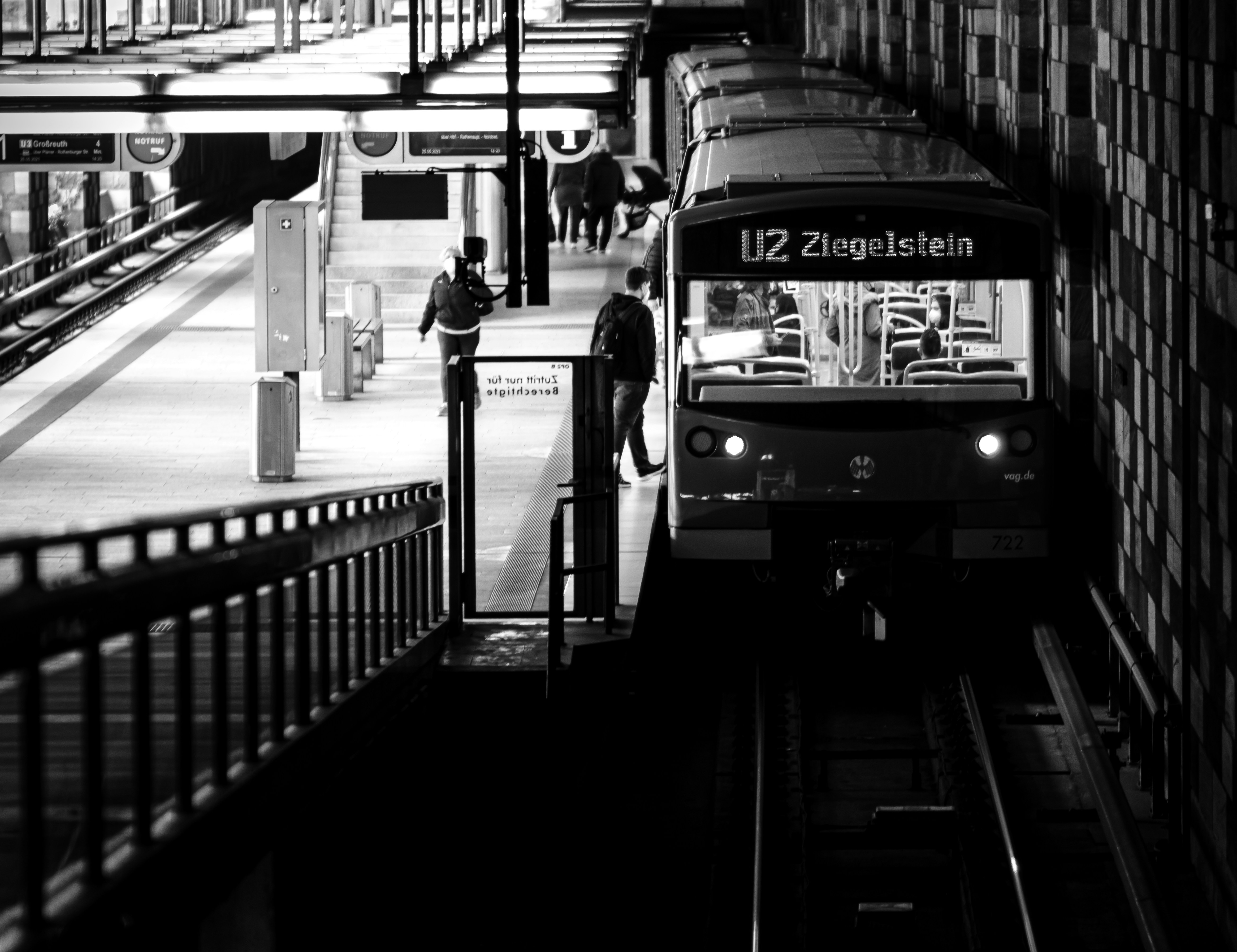 Black and white photograph of a subway train at the platform with passengers boarding.