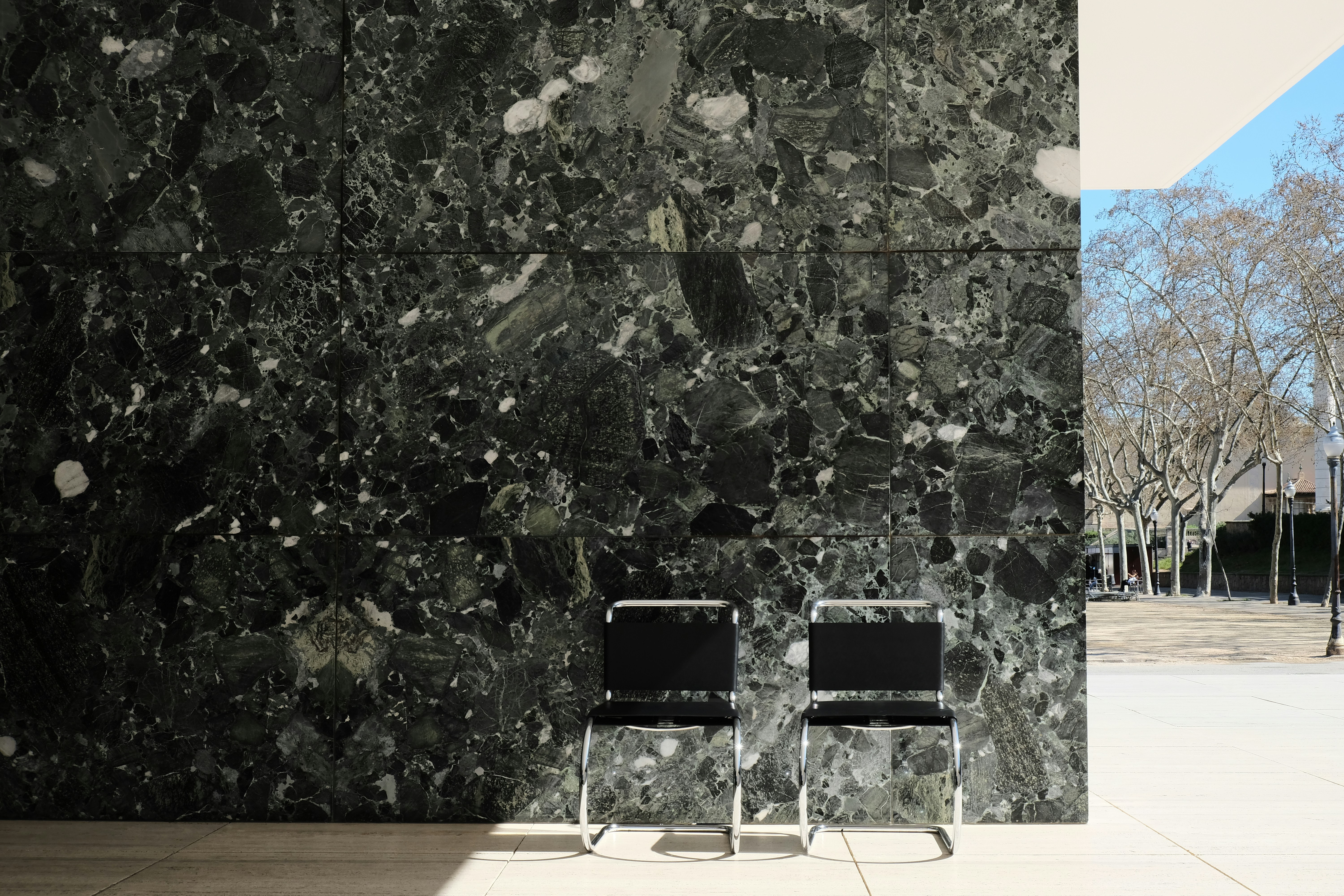 Minimalist Geometry: Two Chrome Chairs Against a Marble Facade