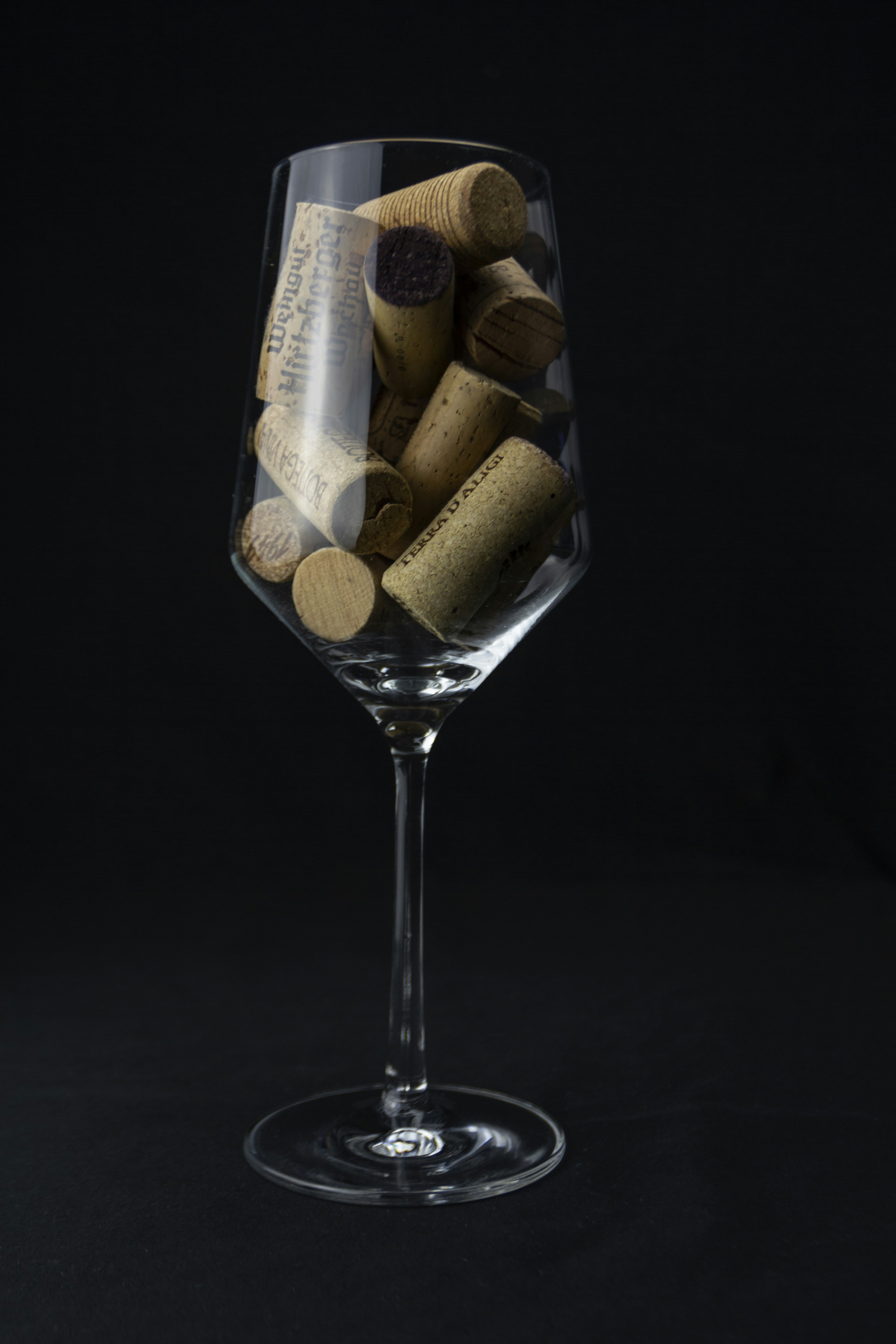 A wine glass filled with wine corks on a black background photo – Free ...