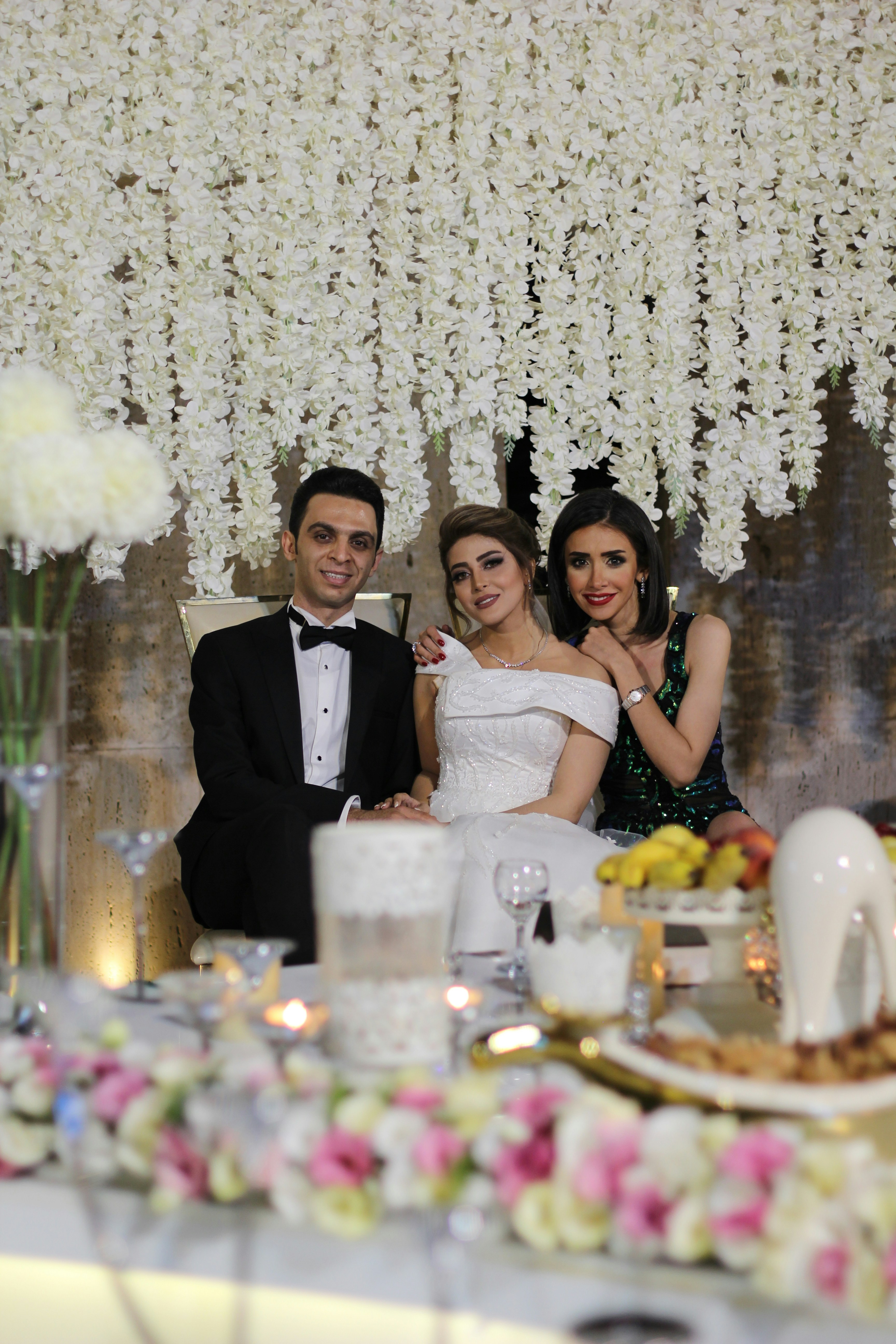 Under the Ivory Cascade: a wedding trio framed by hanging blooms