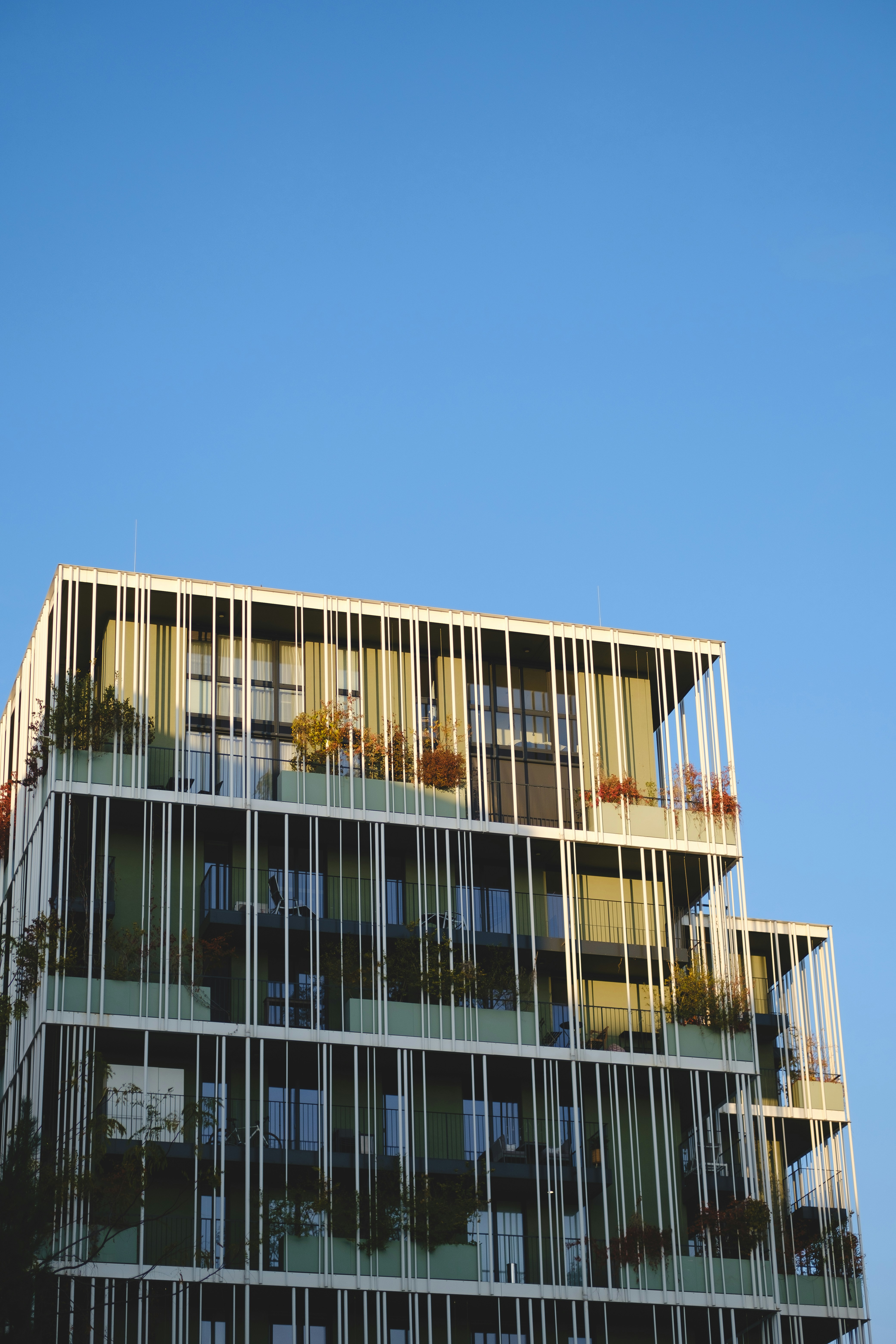 Modern building featuring a striking façade with vertical garden elements and balconies adorned with greenery.