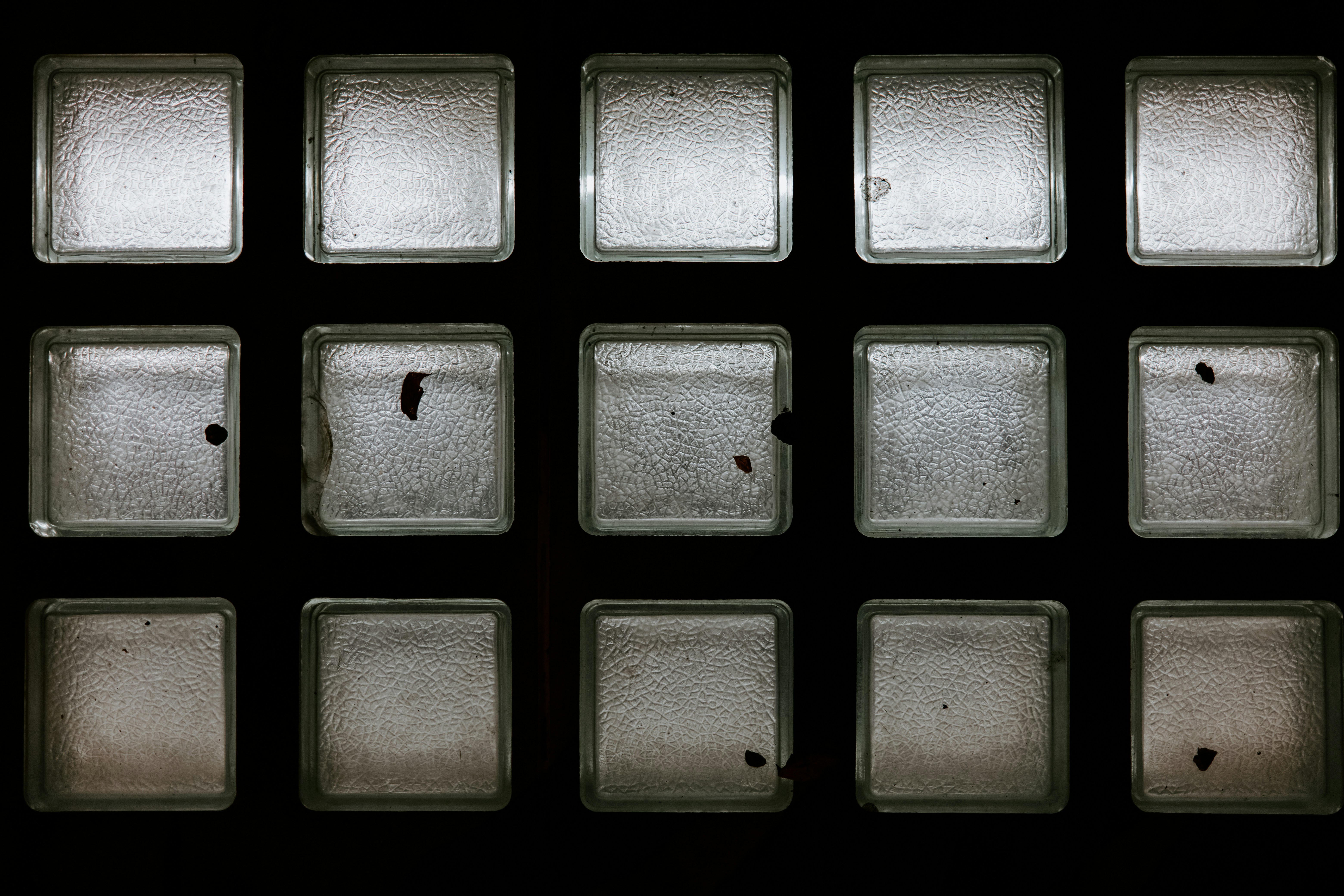 Grid of frosted glass blocks with imperfections, creating an abstract play of light and shadow.