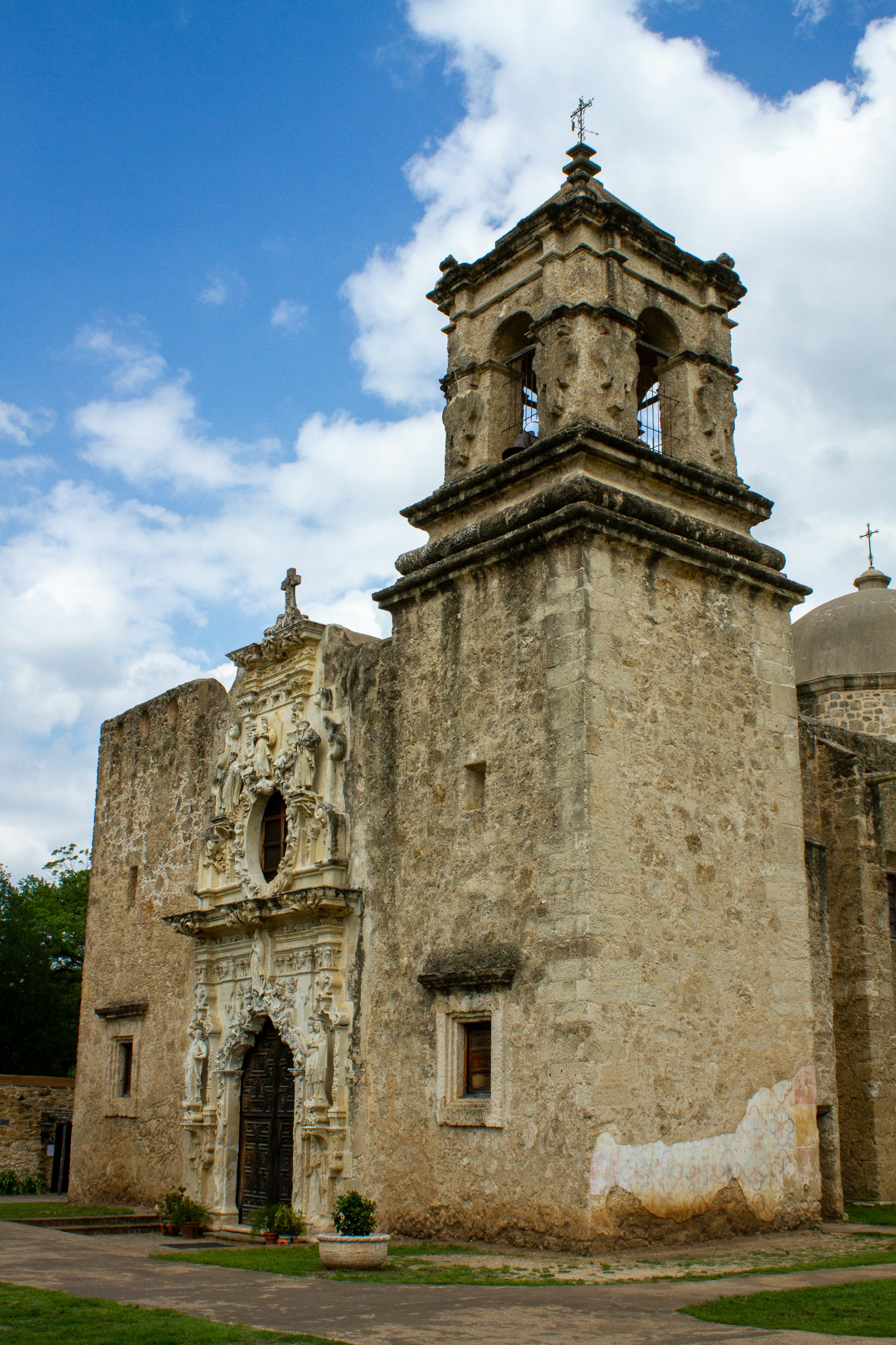 Weathered Bell Tower Rising from the Church Facade Under a Bright Sky