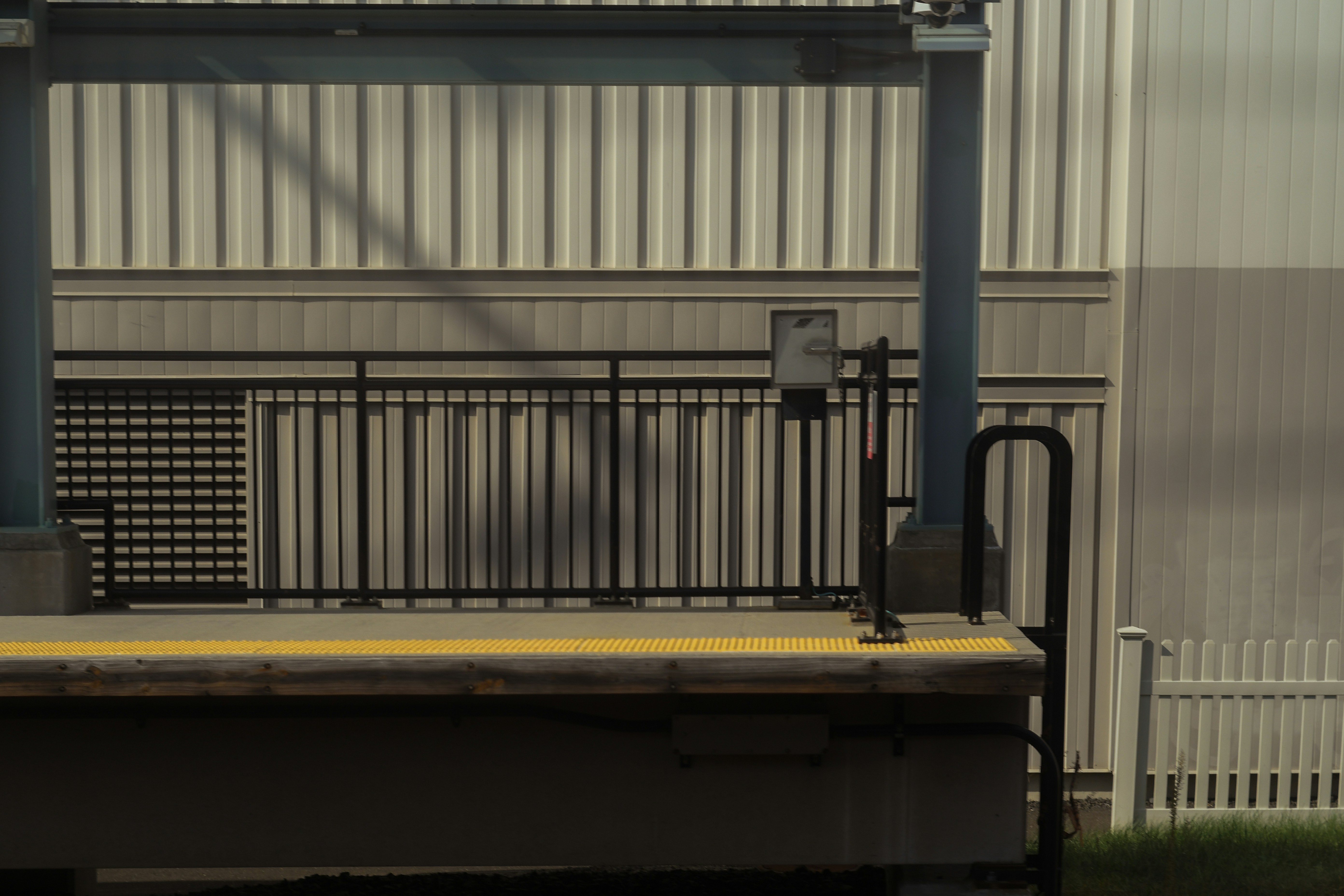 Empty train platform with a yellow safety edge and industrial backdrop, highlighting the architecture of urban transit spaces.