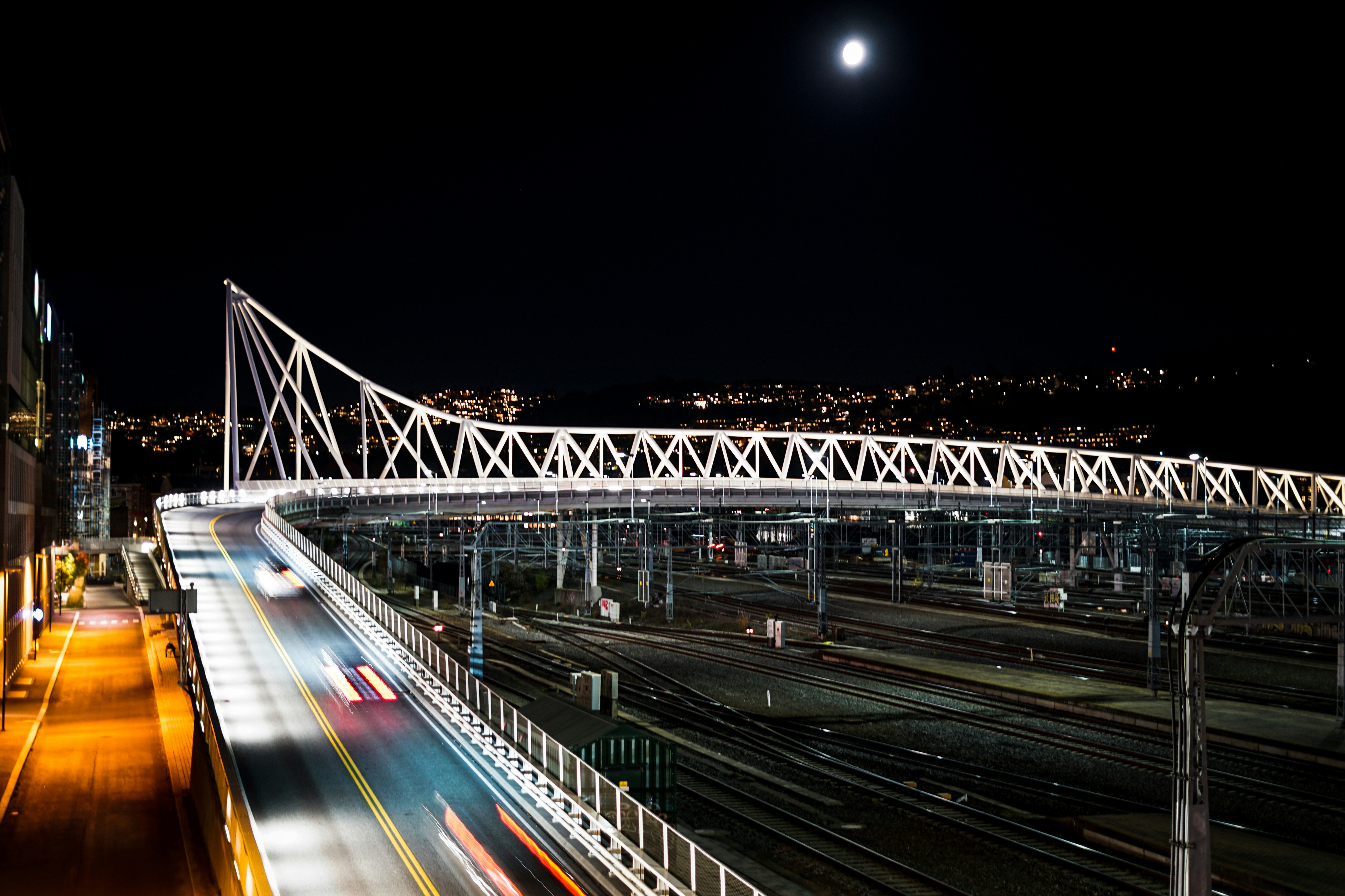 Illuminated Spine: Night Bridge Framing a Quiet Rail Yard