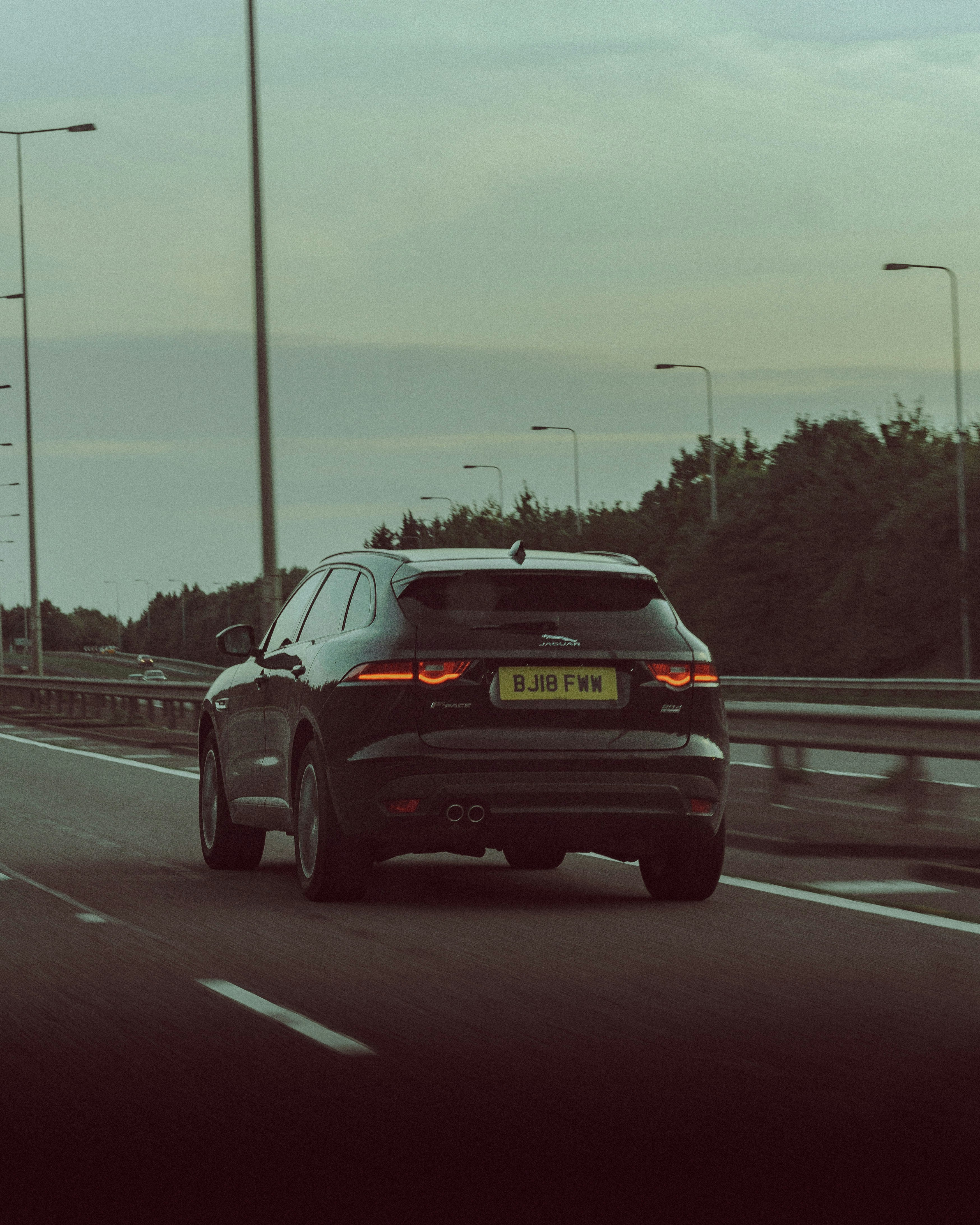 Tail-Lit Retreat: A Black SUV Bends the Dusk on the Open Road