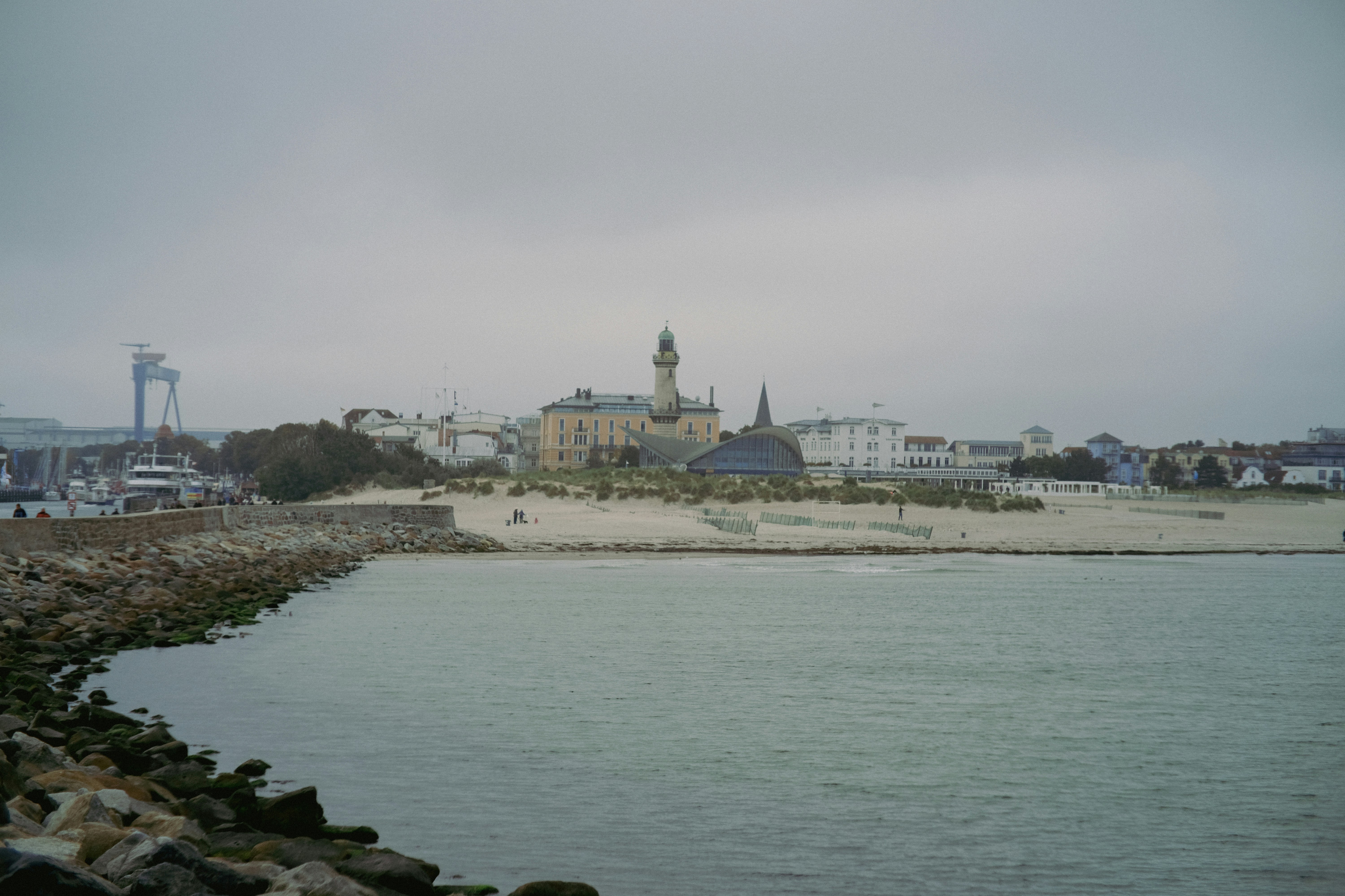 Overcast sky over a coastal town with a prominent clock tower and sandy beach.