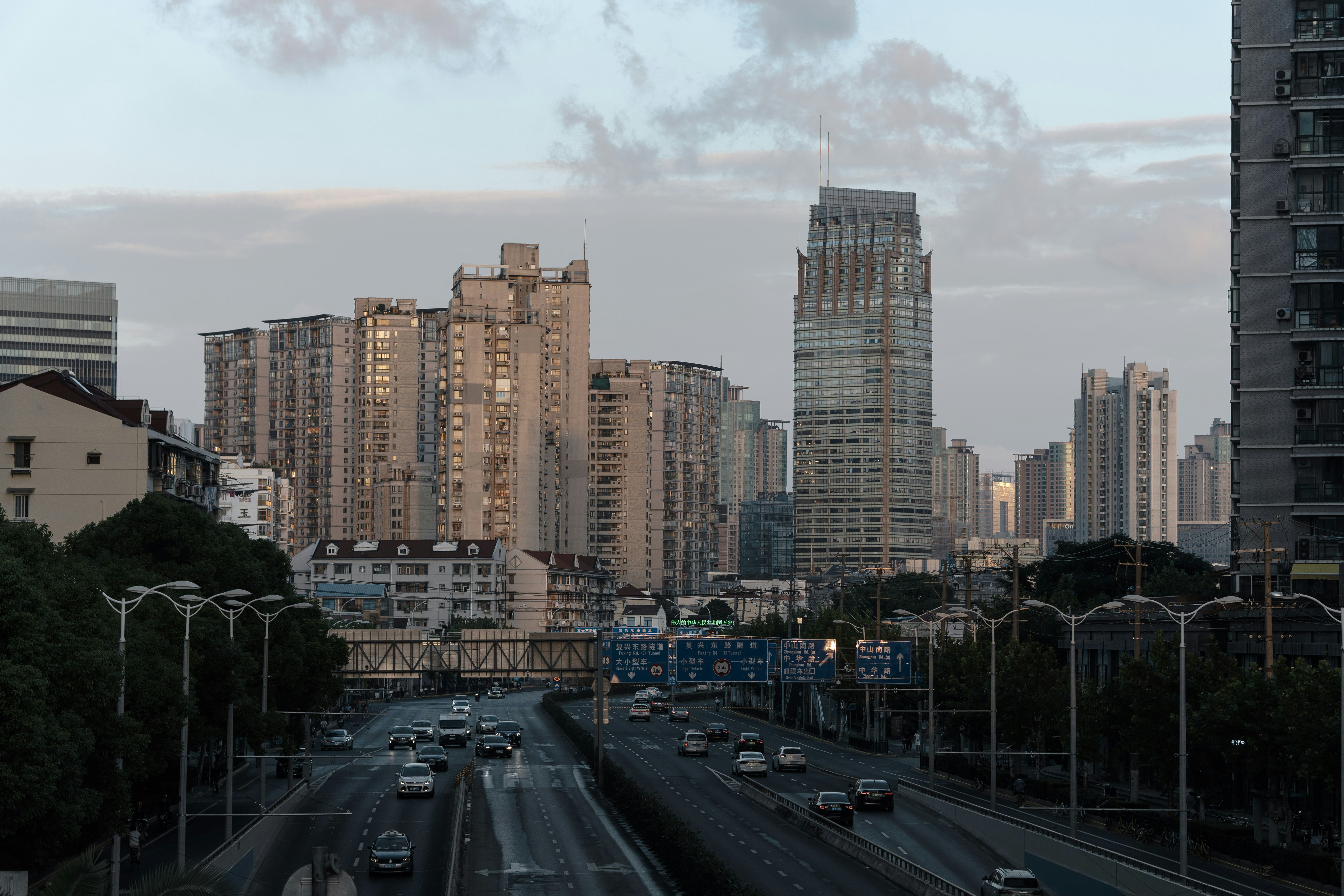 City skyline at dusk, showcasing a blend of modern architecture and bustling traffic on a highway below.