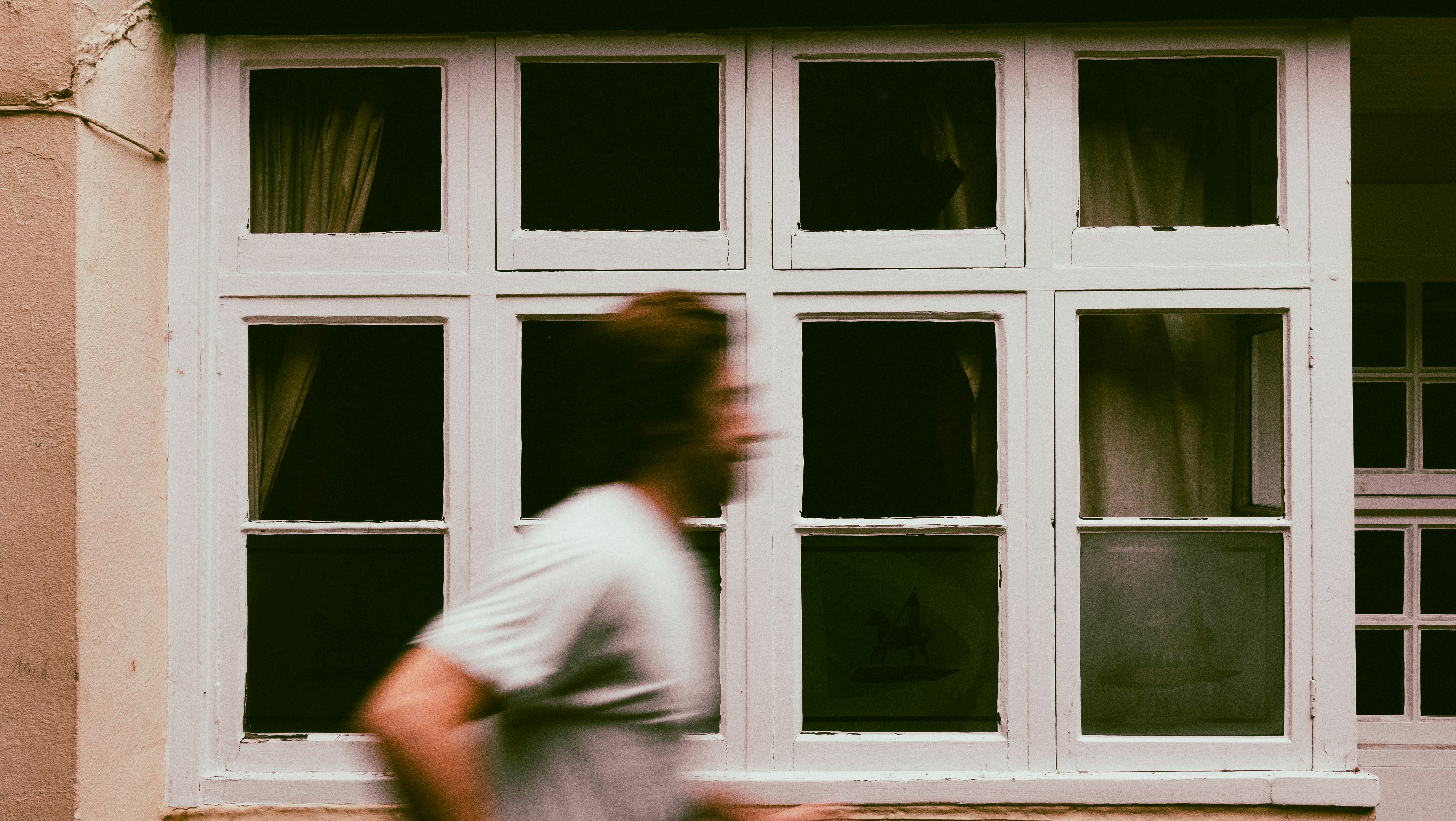 A man walking past a building with a window photo – Free Oxford Image ...