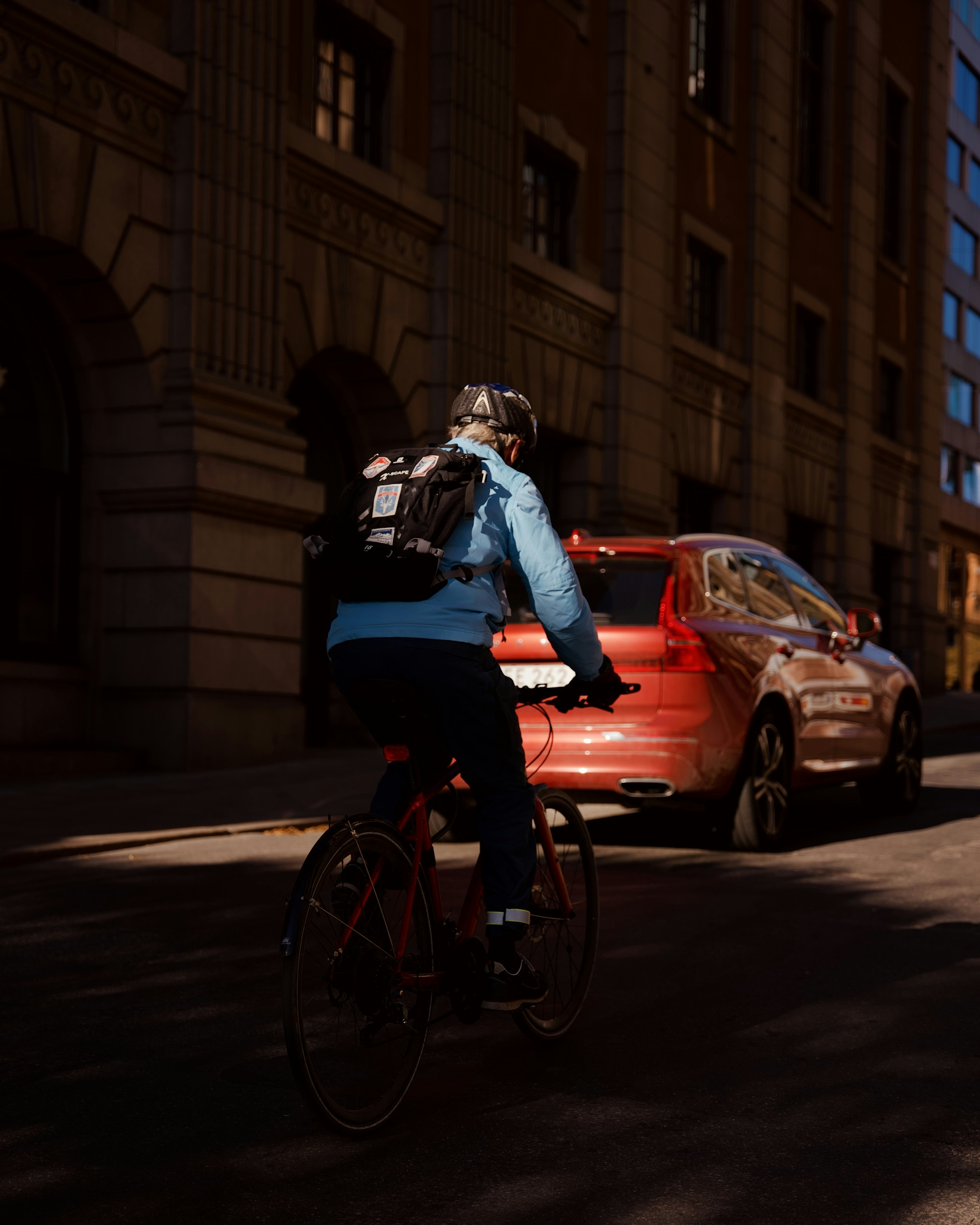 Blue-clad Cyclist Crossing a Quiet Urban Street at Dusk