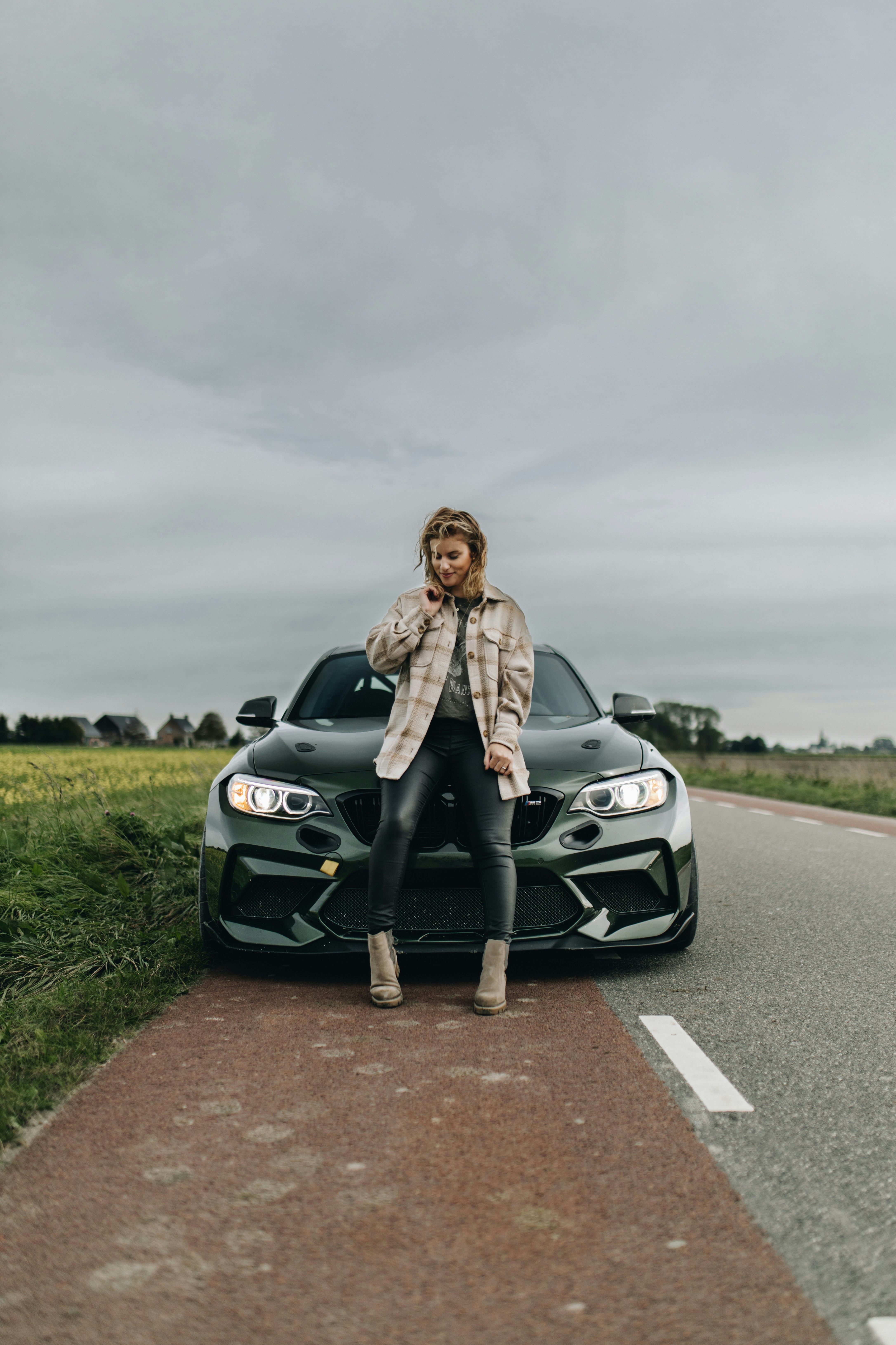Front-Row Confidence: Woman and Matte Green Sports Car on a Quiet Road