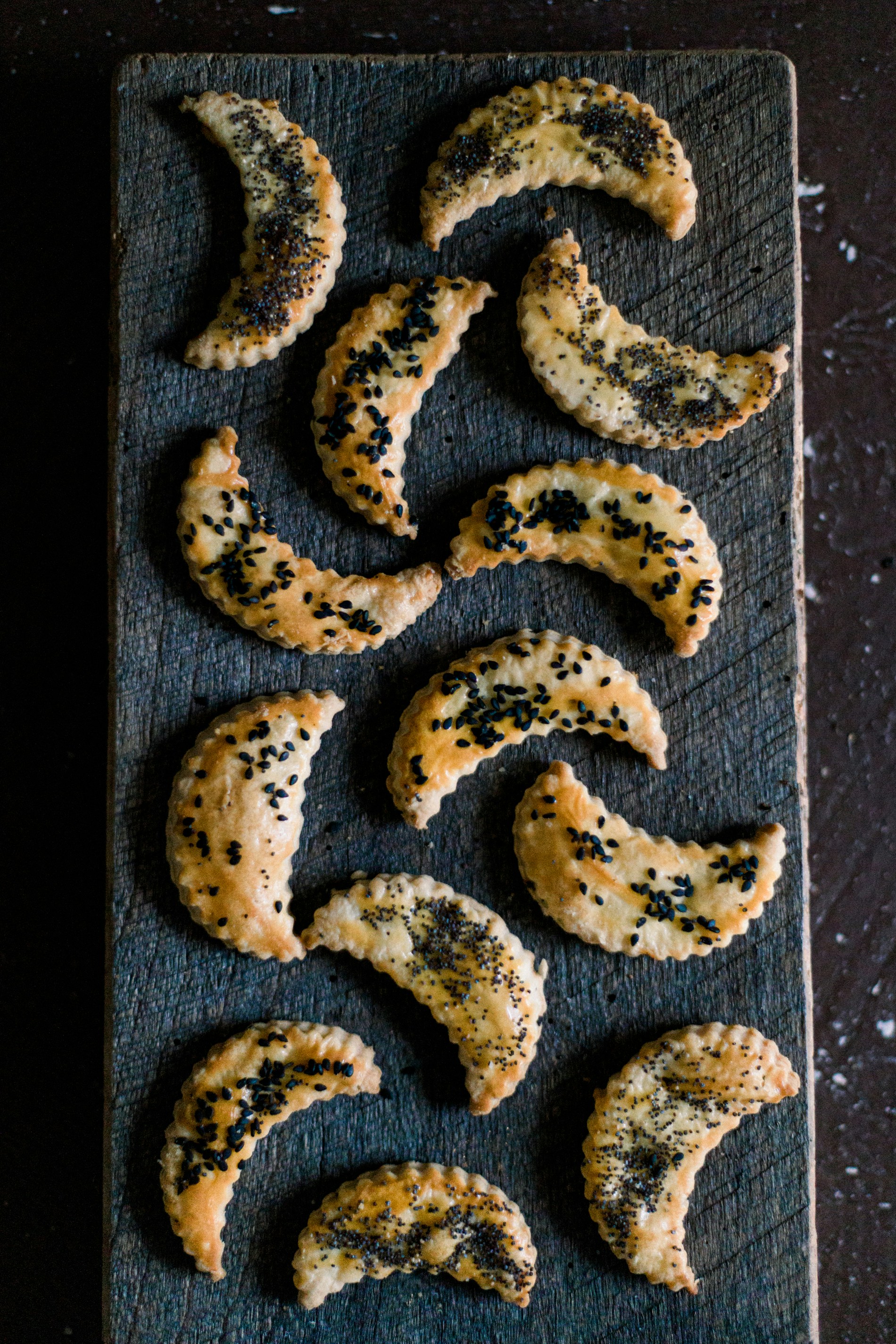 Sesame-Top Crescent Cookies on a Charred Board
