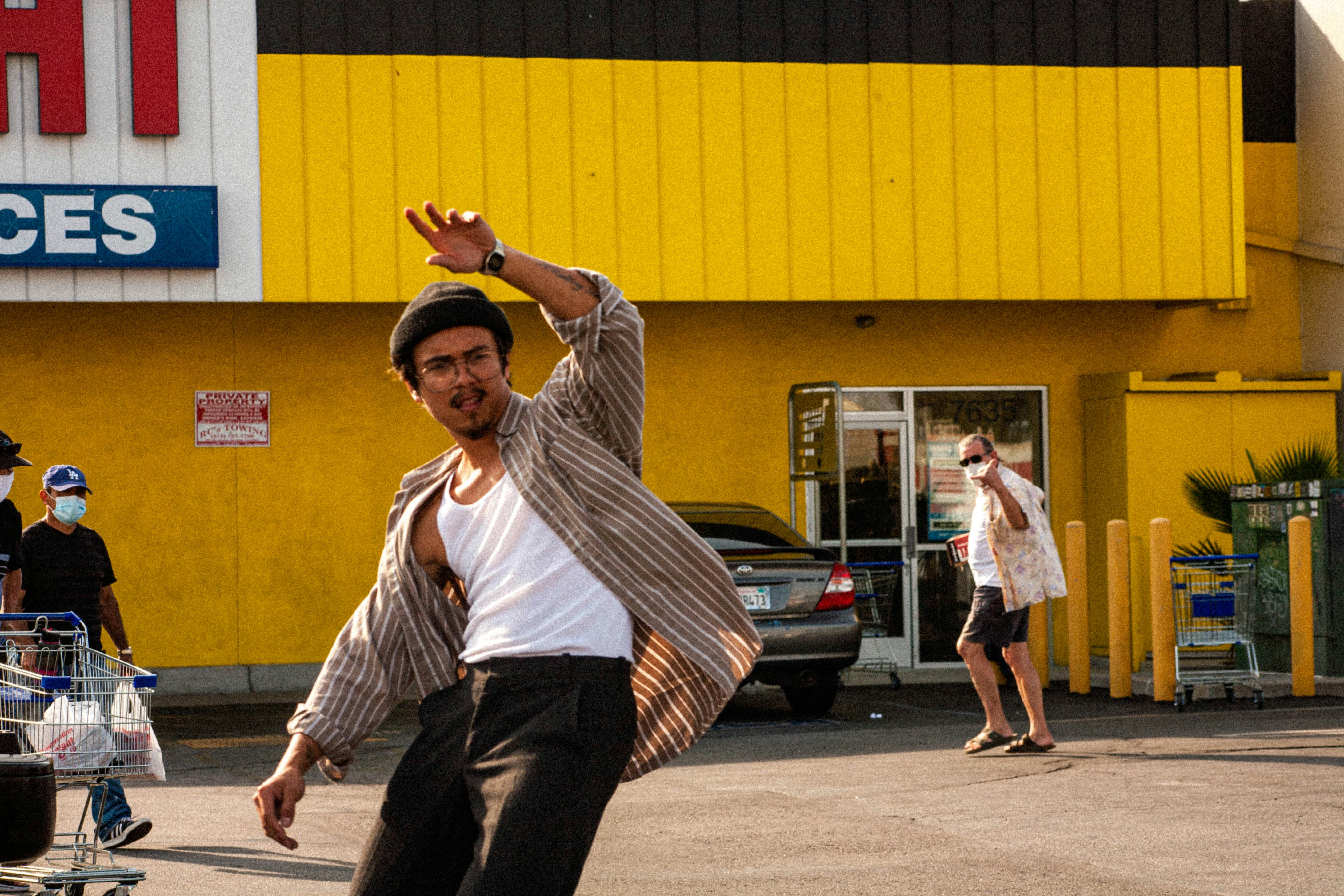 Stride Under the Yellow Facade: A Street Dancer's Moment in a Bright Parking Lot