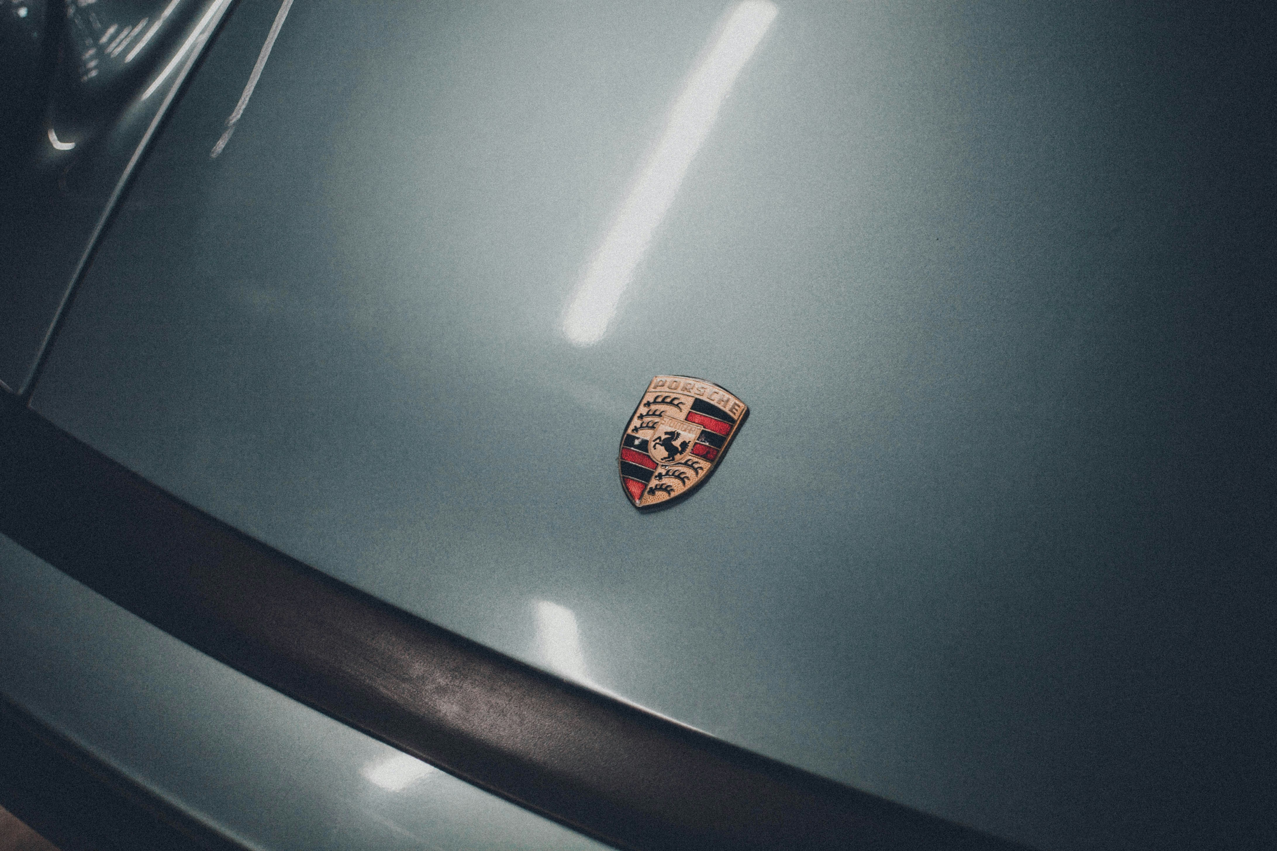 Porsche Crest on Teal Hood Under Neon Reflections
