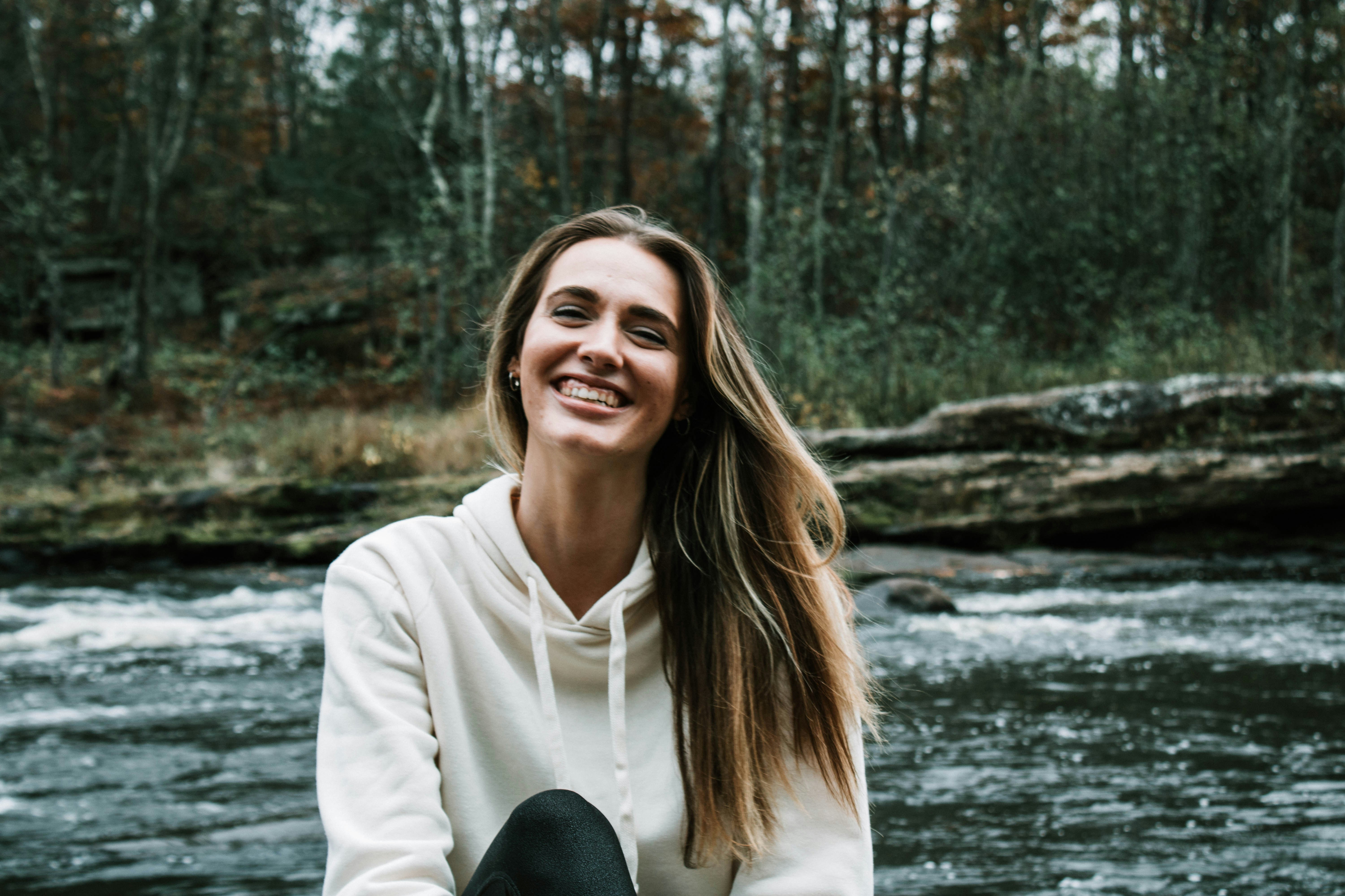 a woman sitting on a rock next to a river