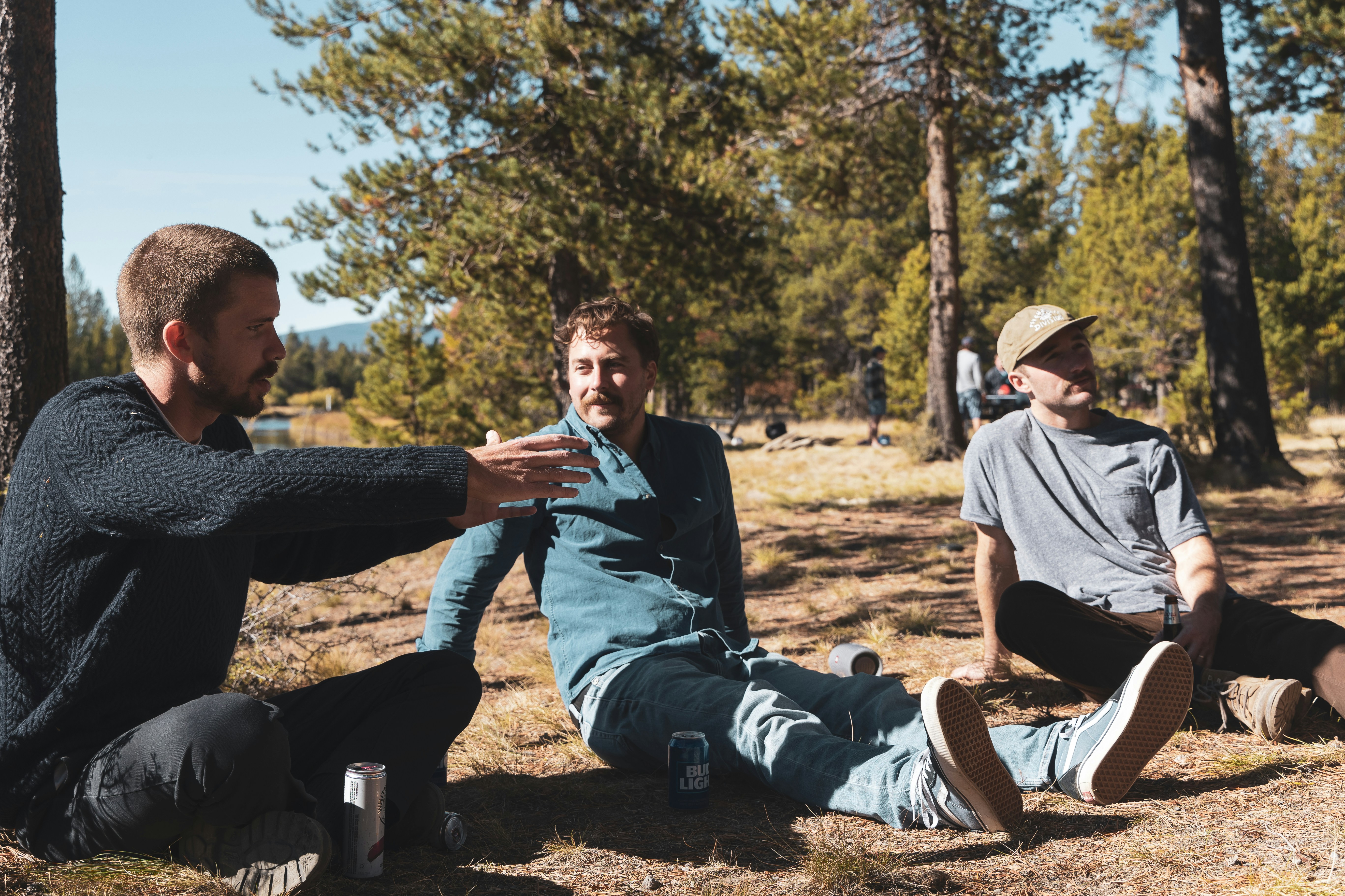 Three men sitting on the ground in the woods photo – Free Happy Image ...