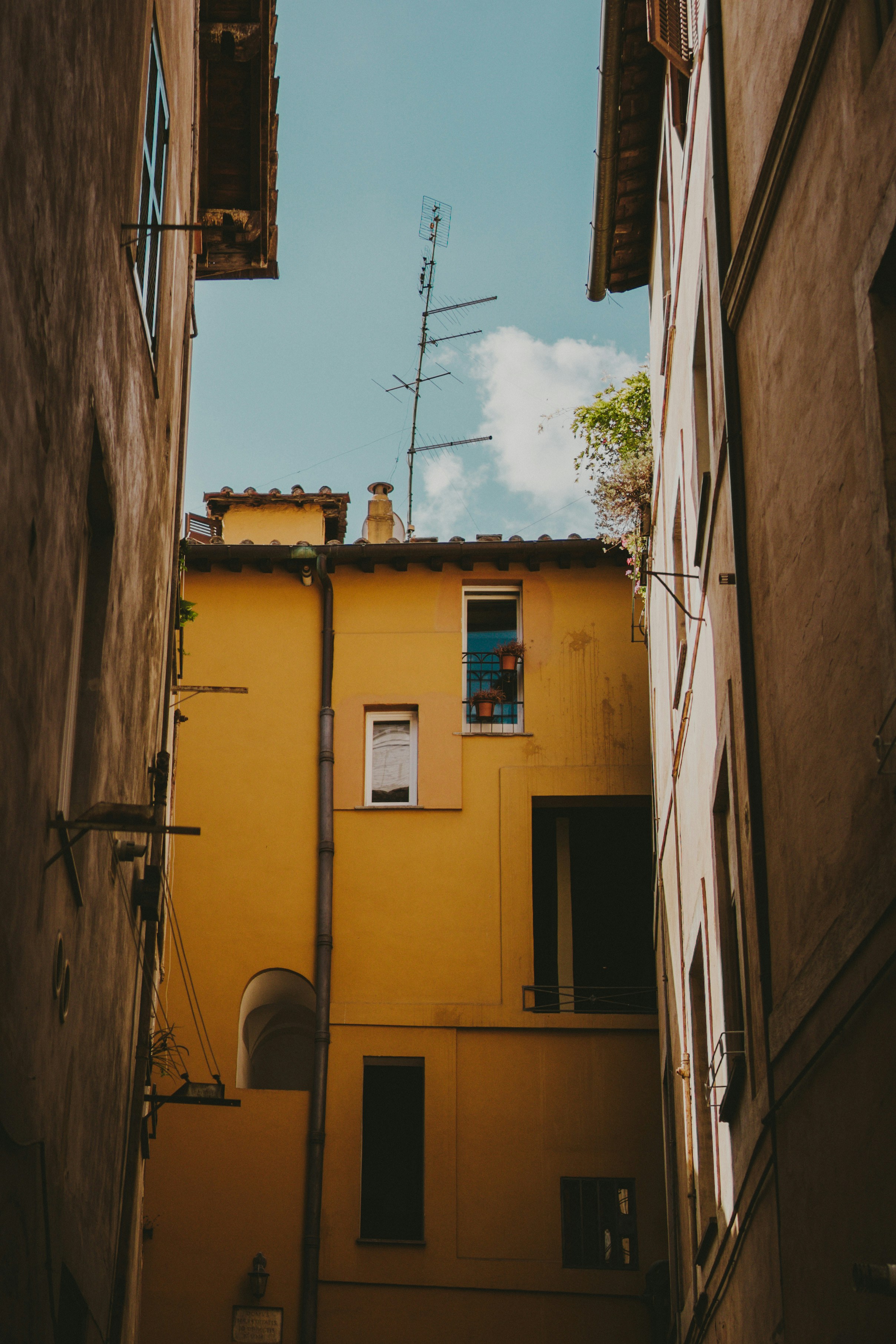 Colorful building facades framed by narrow alley, showcasing vibrant windows and a clear sky above.
