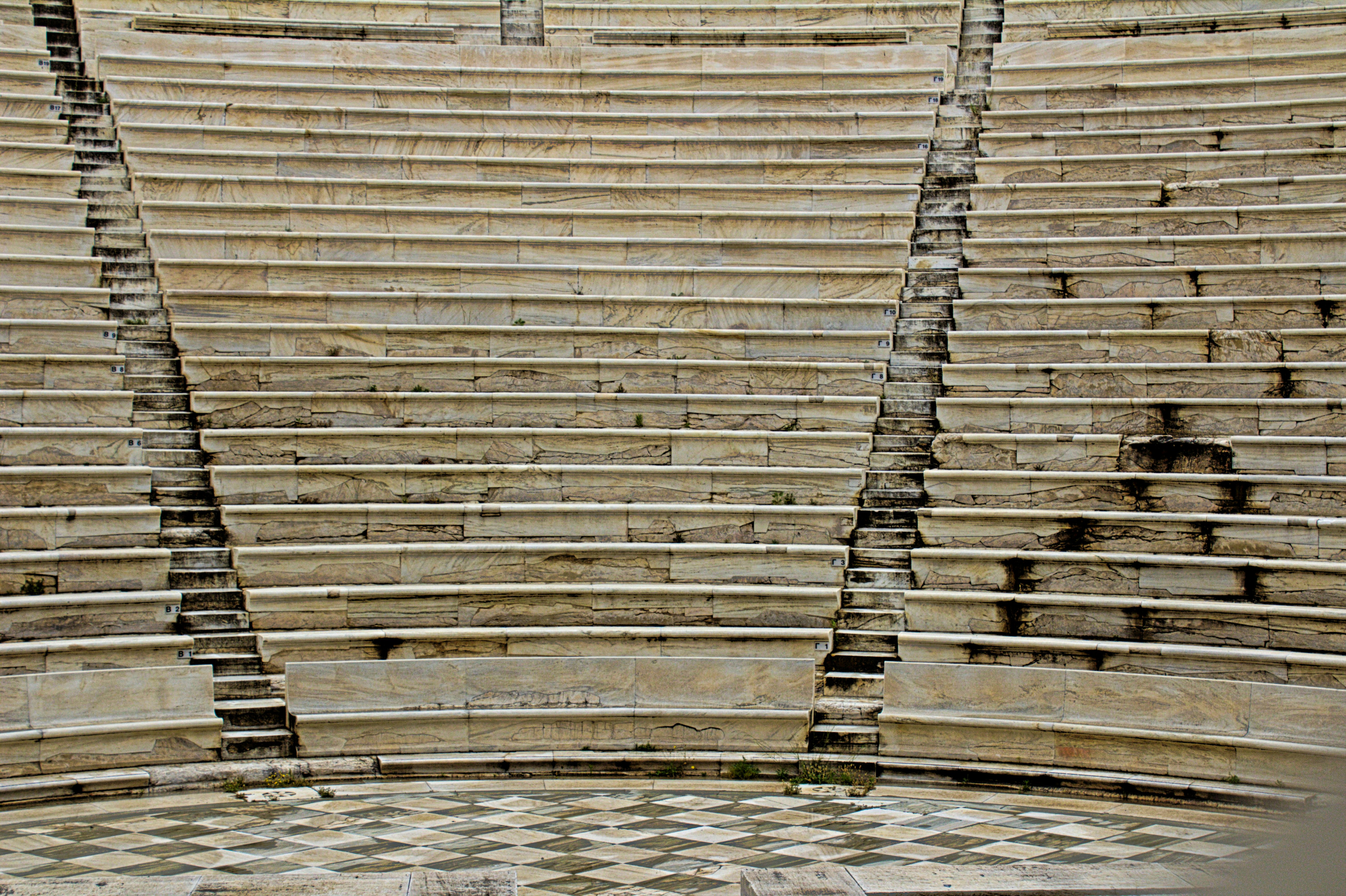 Stone steps of an ancient amphitheater, showcasing the intricate design and weathered texture of the seating. The circular layout invites contemplation of historical gatherings.
