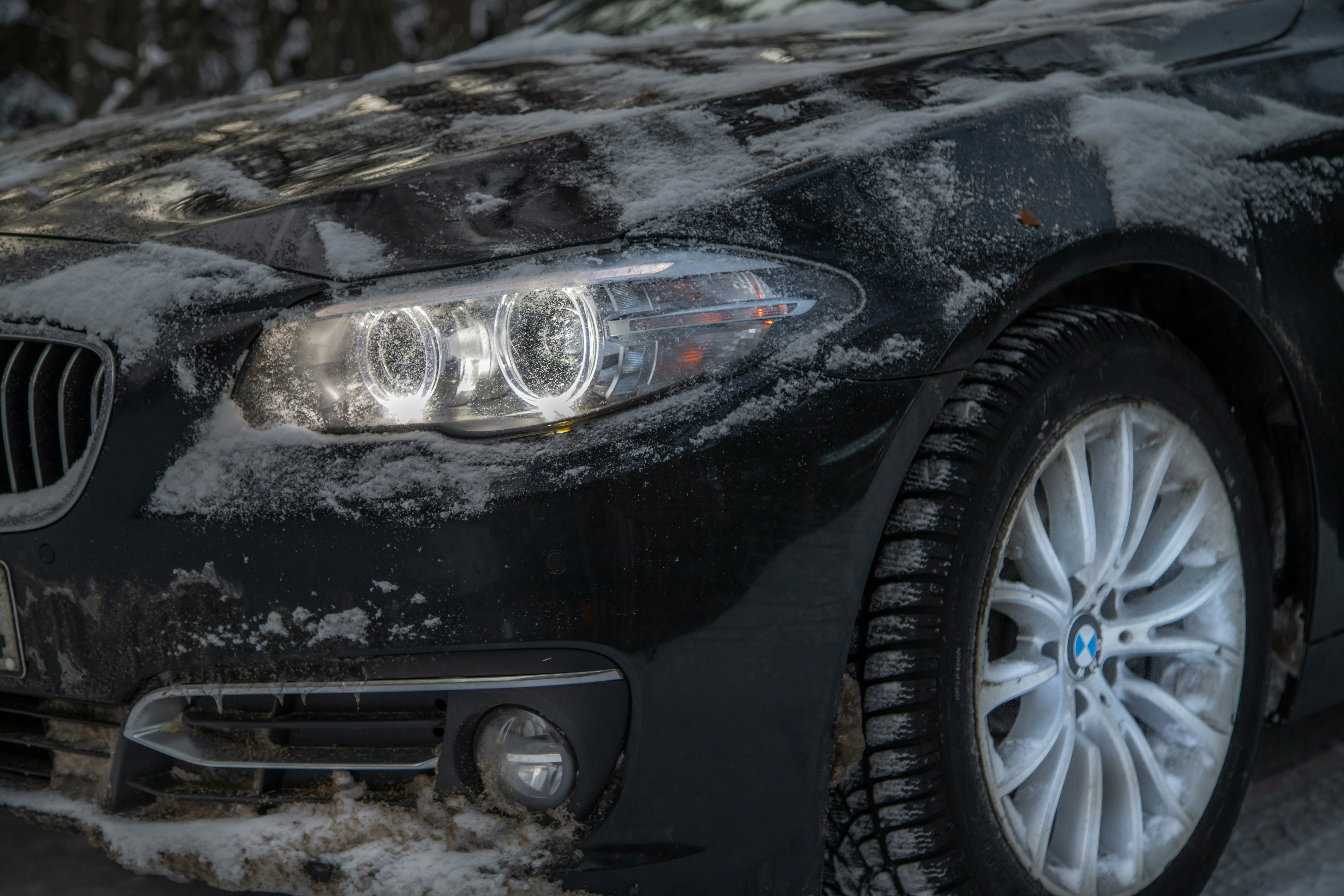 Snowbound BMW: Headlight Glint Amid Frosted Curves
