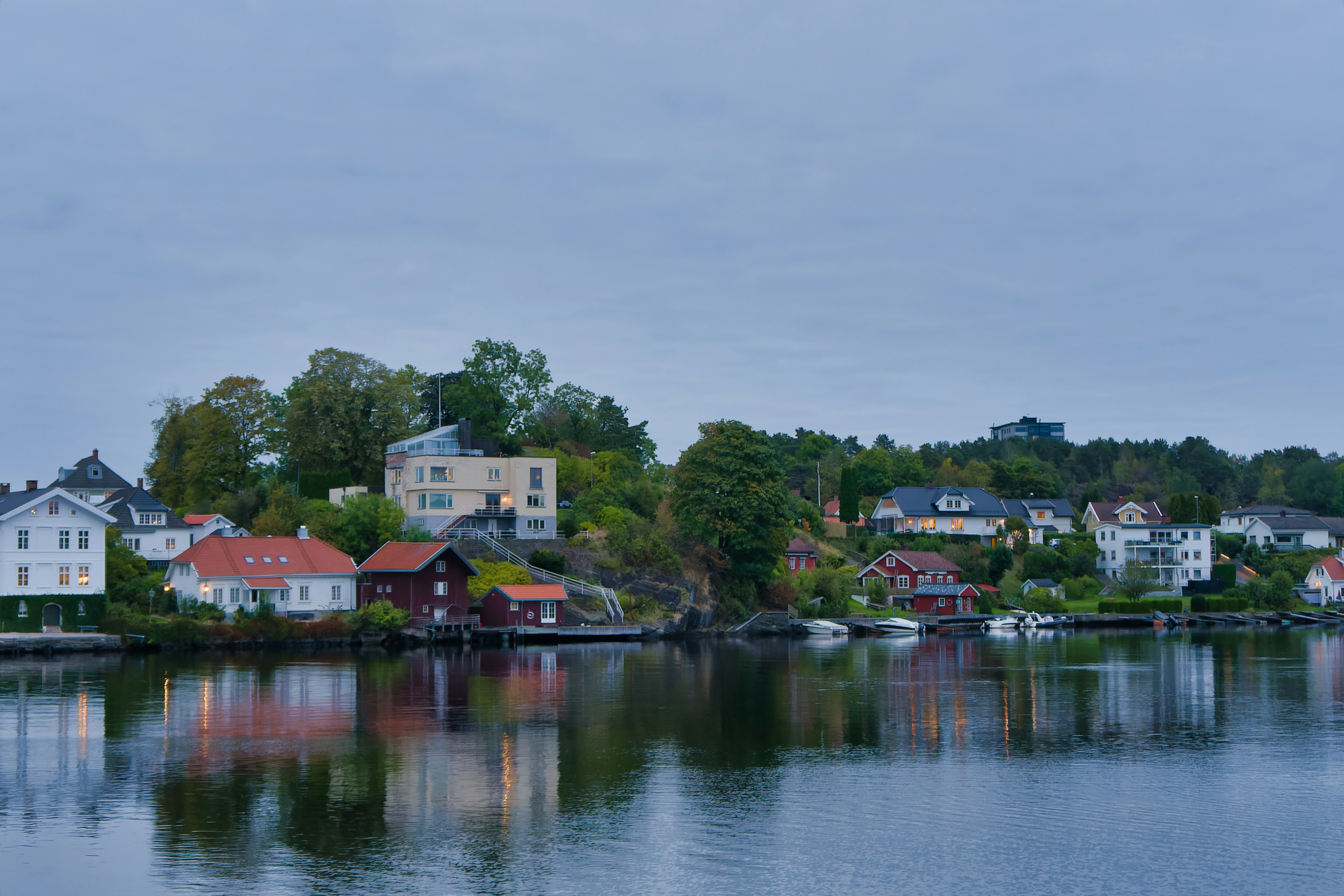 a body of water with houses on a hill in the background