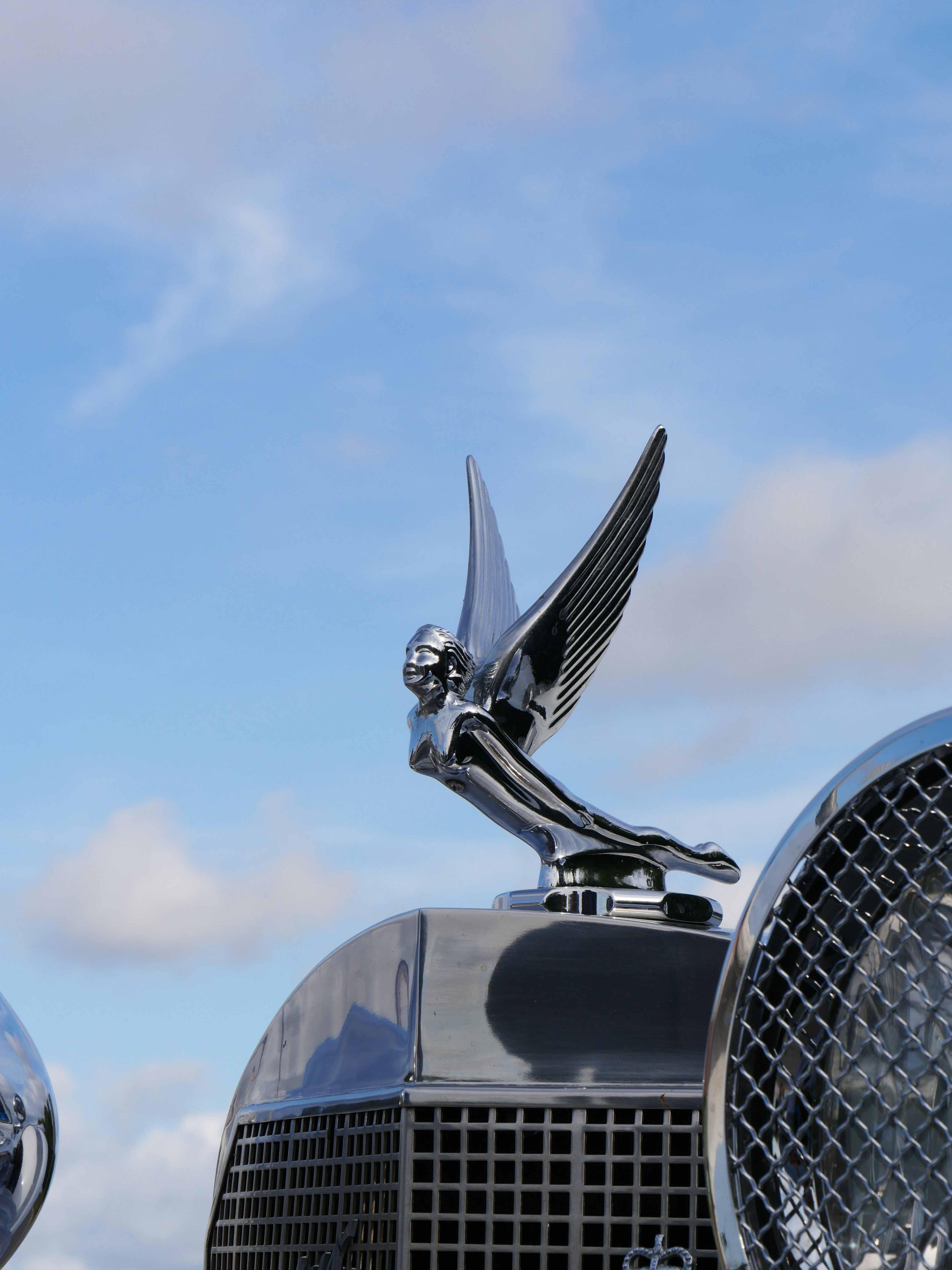 Winged Chrome Guardian Crowns a Vintage Hood Under a Clear Blue Sky