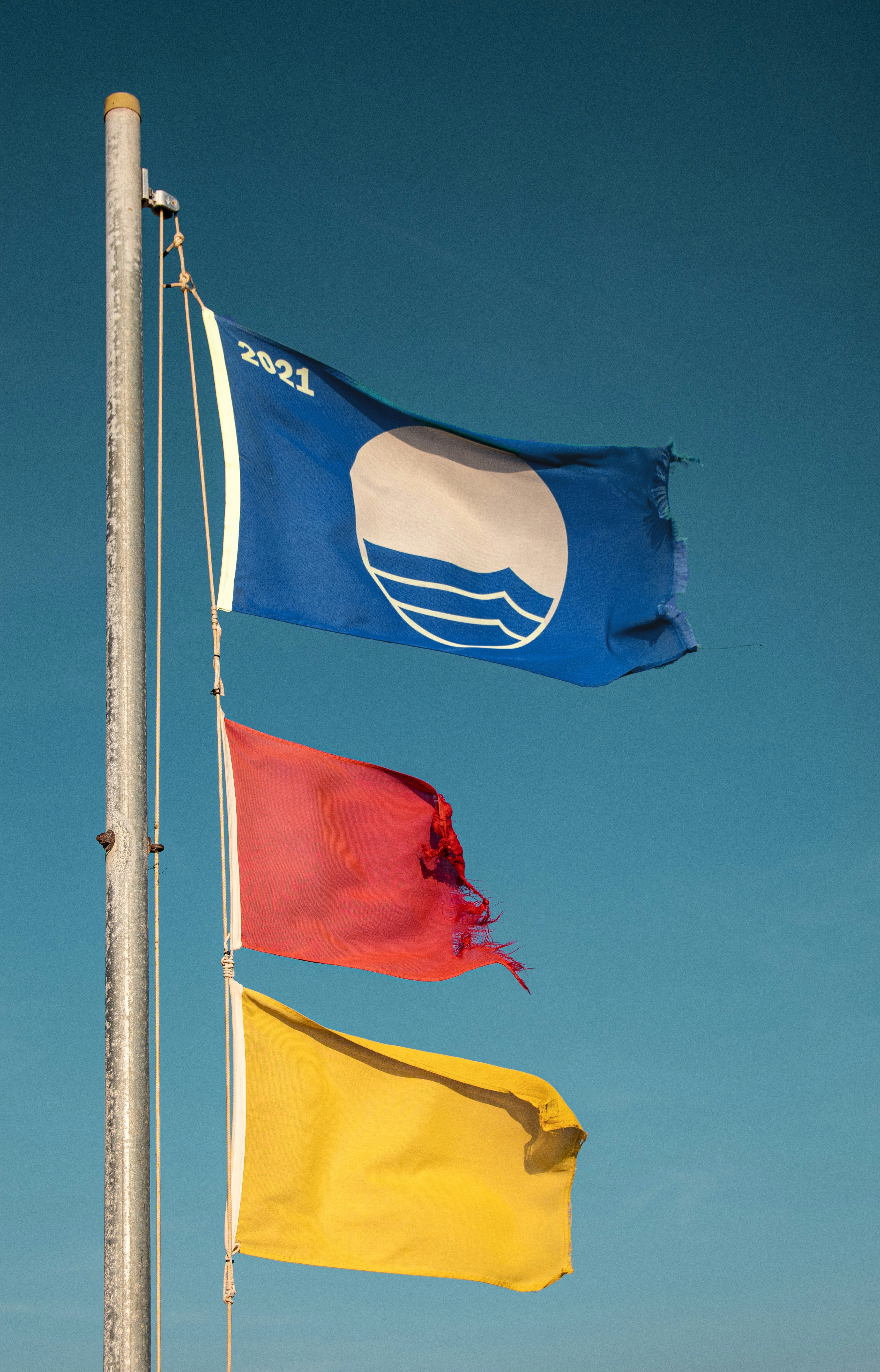 Un grupo de tres banderas ondeando una al lado de la otra foto – Imagen ...