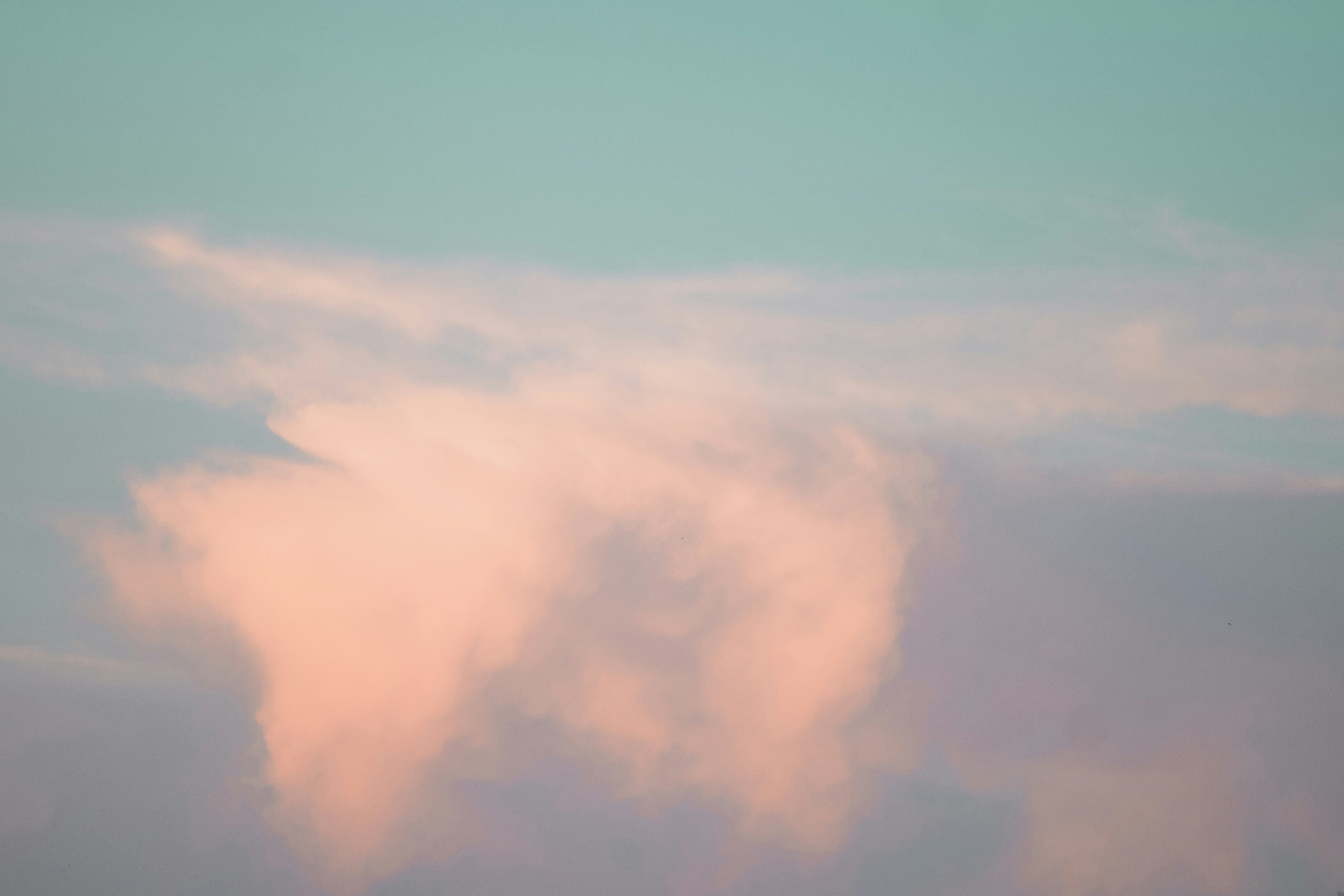 a plane flying in the sky with a pink cloud in the background